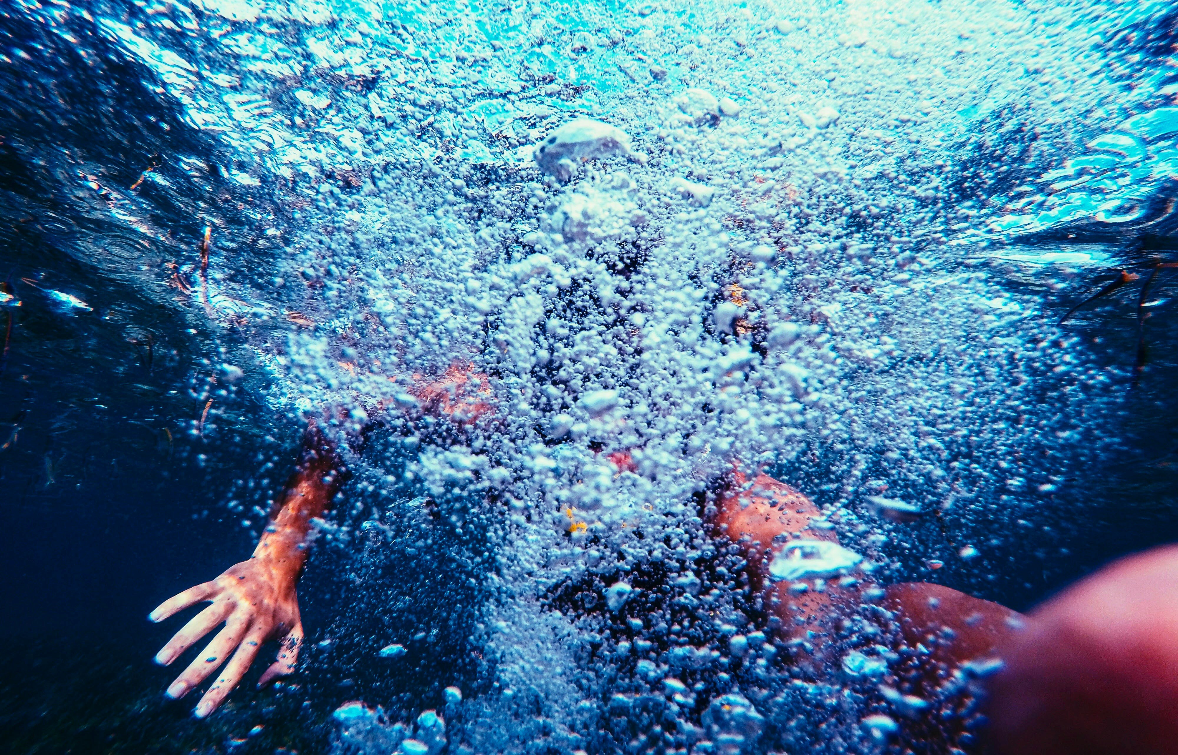 Person submerged underwater surrounded by a cascade of bubbles.