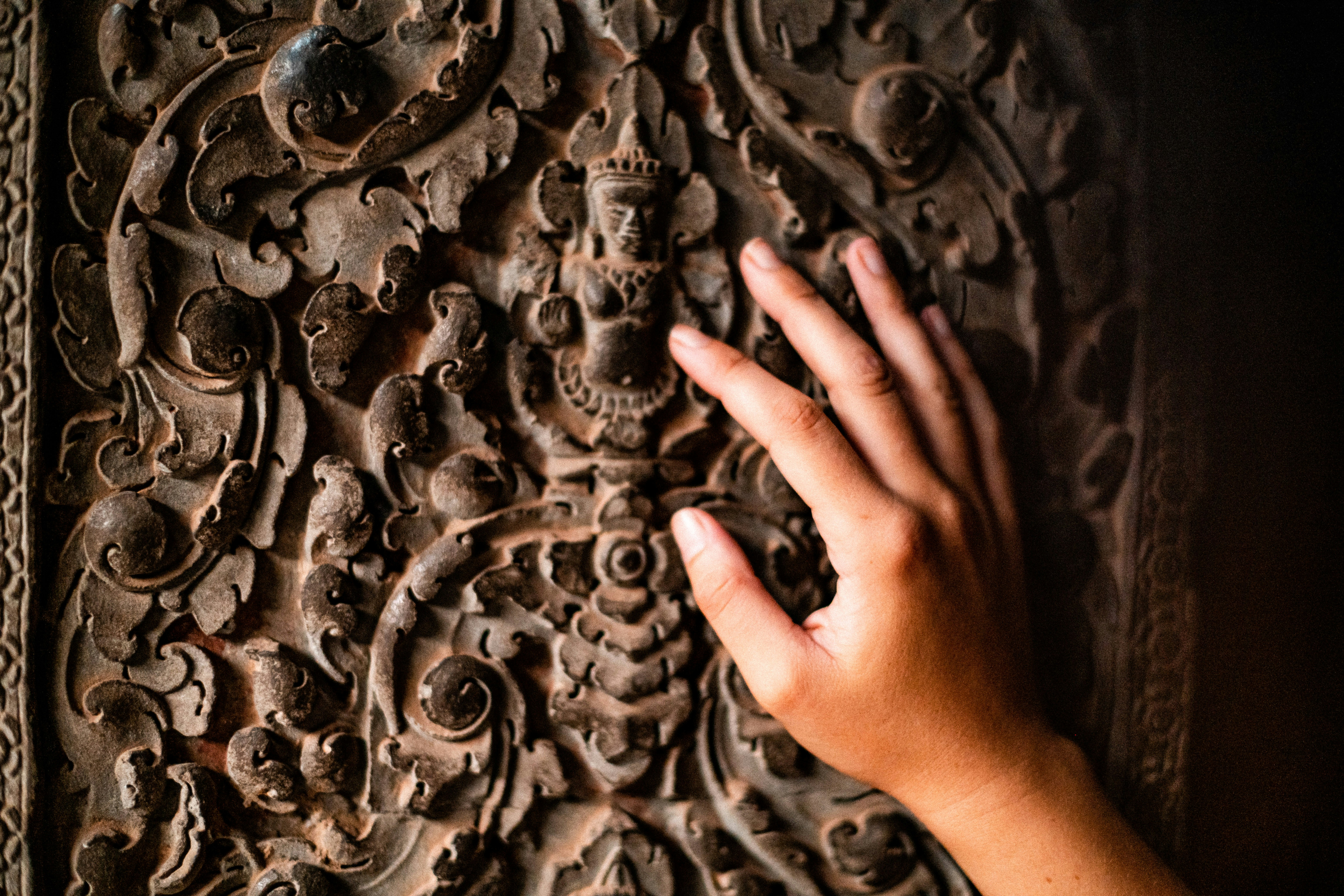 Hand on Time-Worn Carving: Tracing Light Across an Ornate Relief