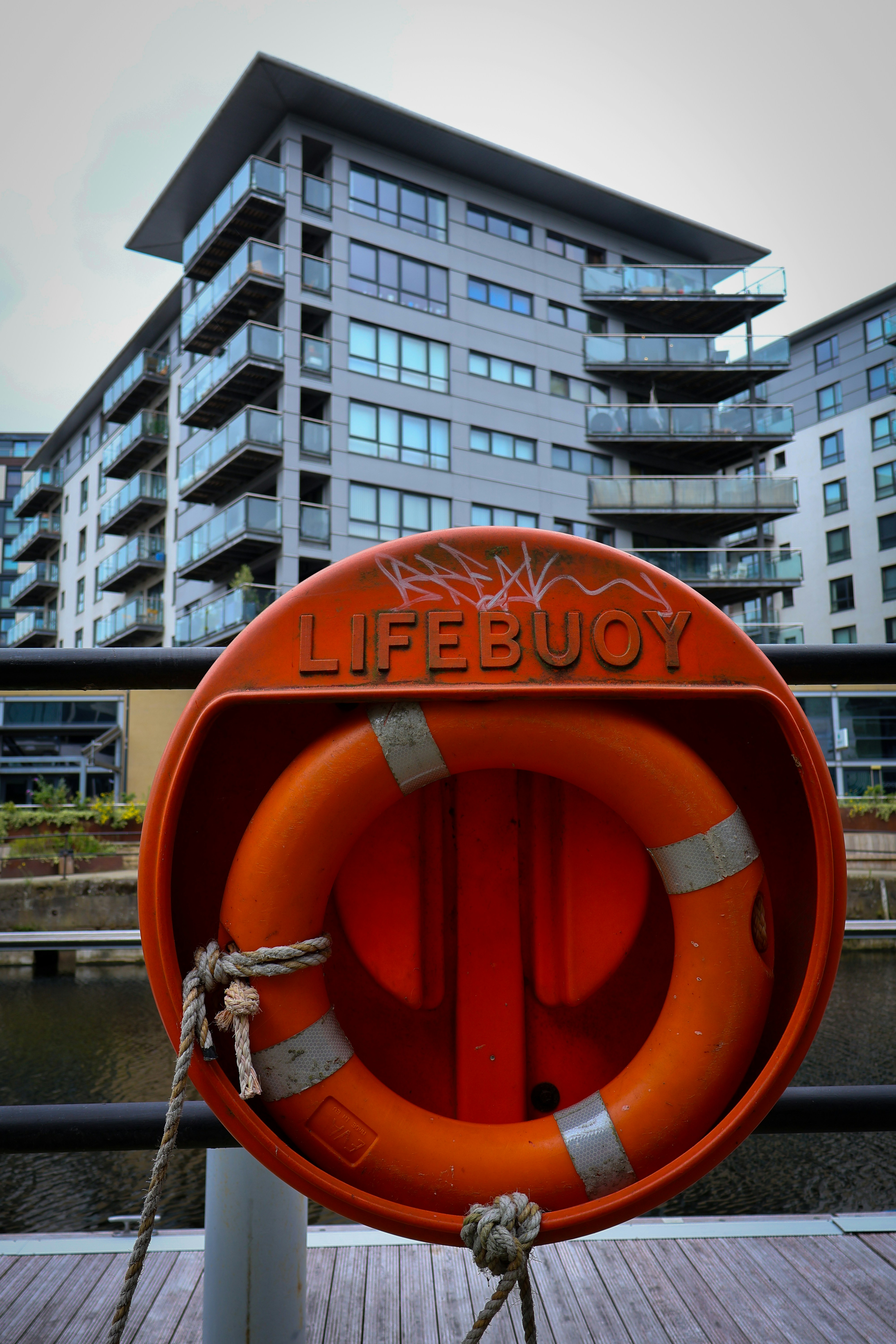 Orange Sentinel at Waterside: Lifebuoy Framing a Modern Waterfront