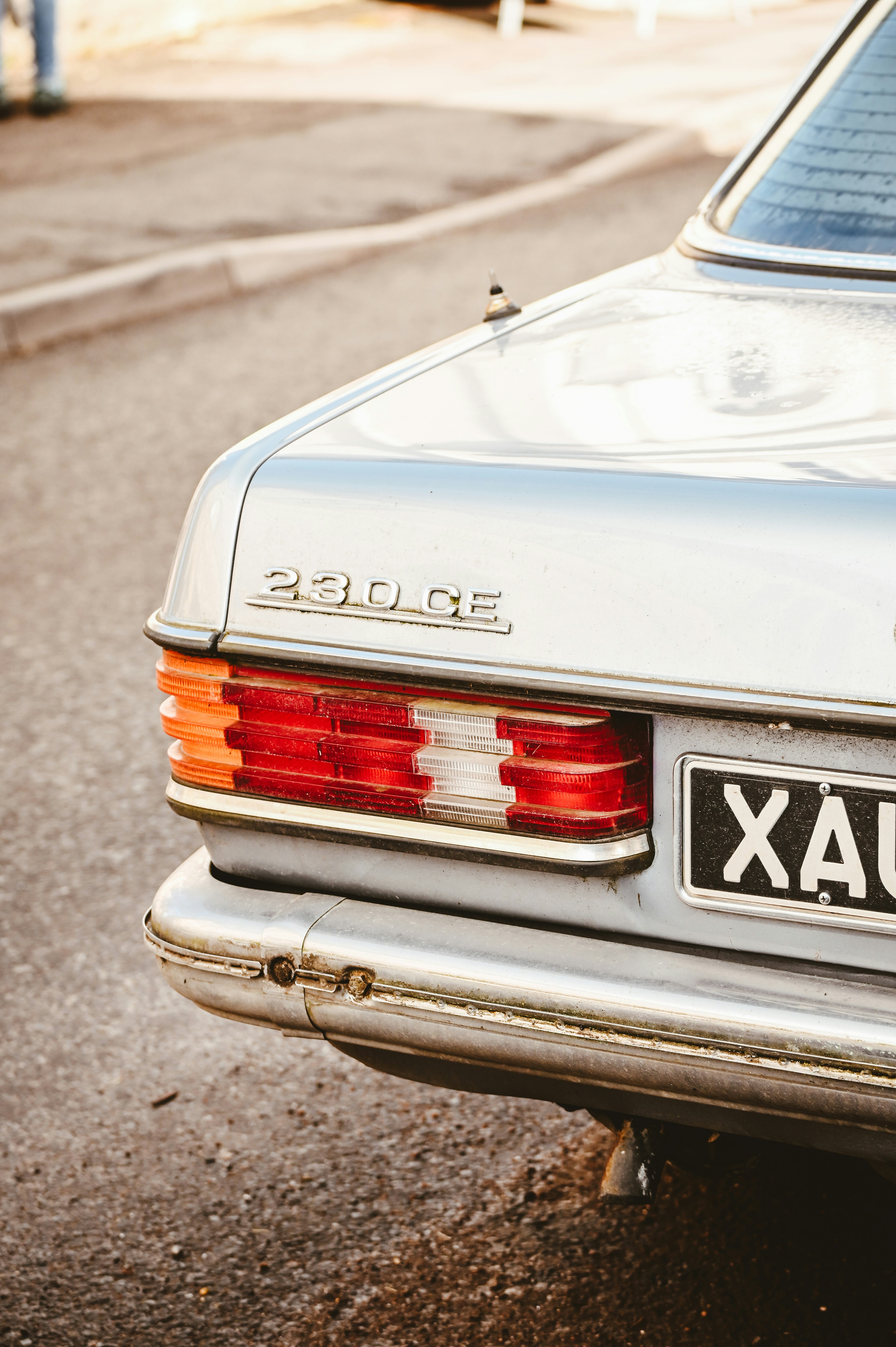 Close-up of a vintage car's rear with distinctive taillights and chrome details in warm sunlight.