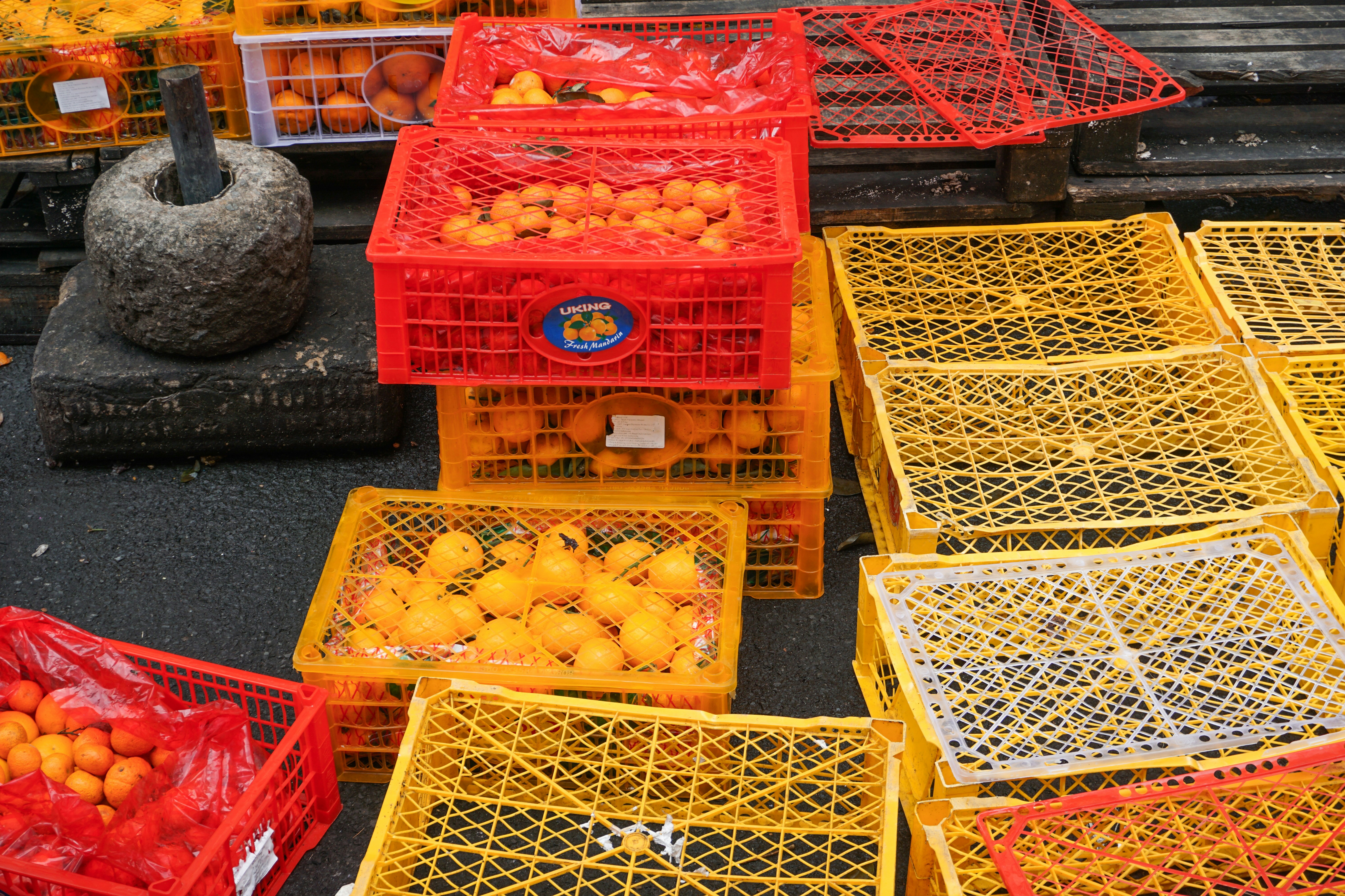 Colorful crates filled with oranges stacked at an outdoor market.