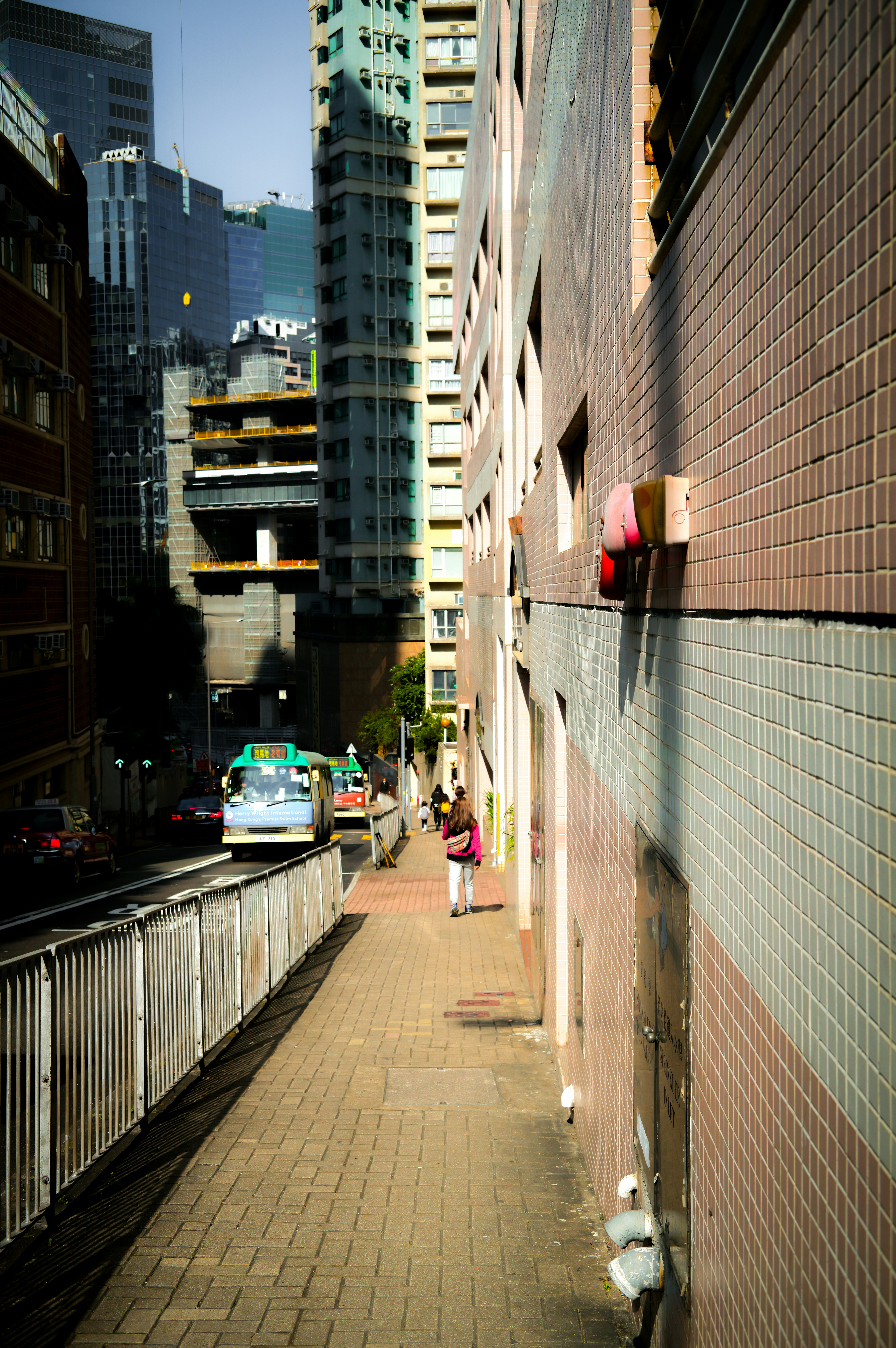 Sunlit Narrow Street: A Lone Pedestrian Amid Towering City Blocks