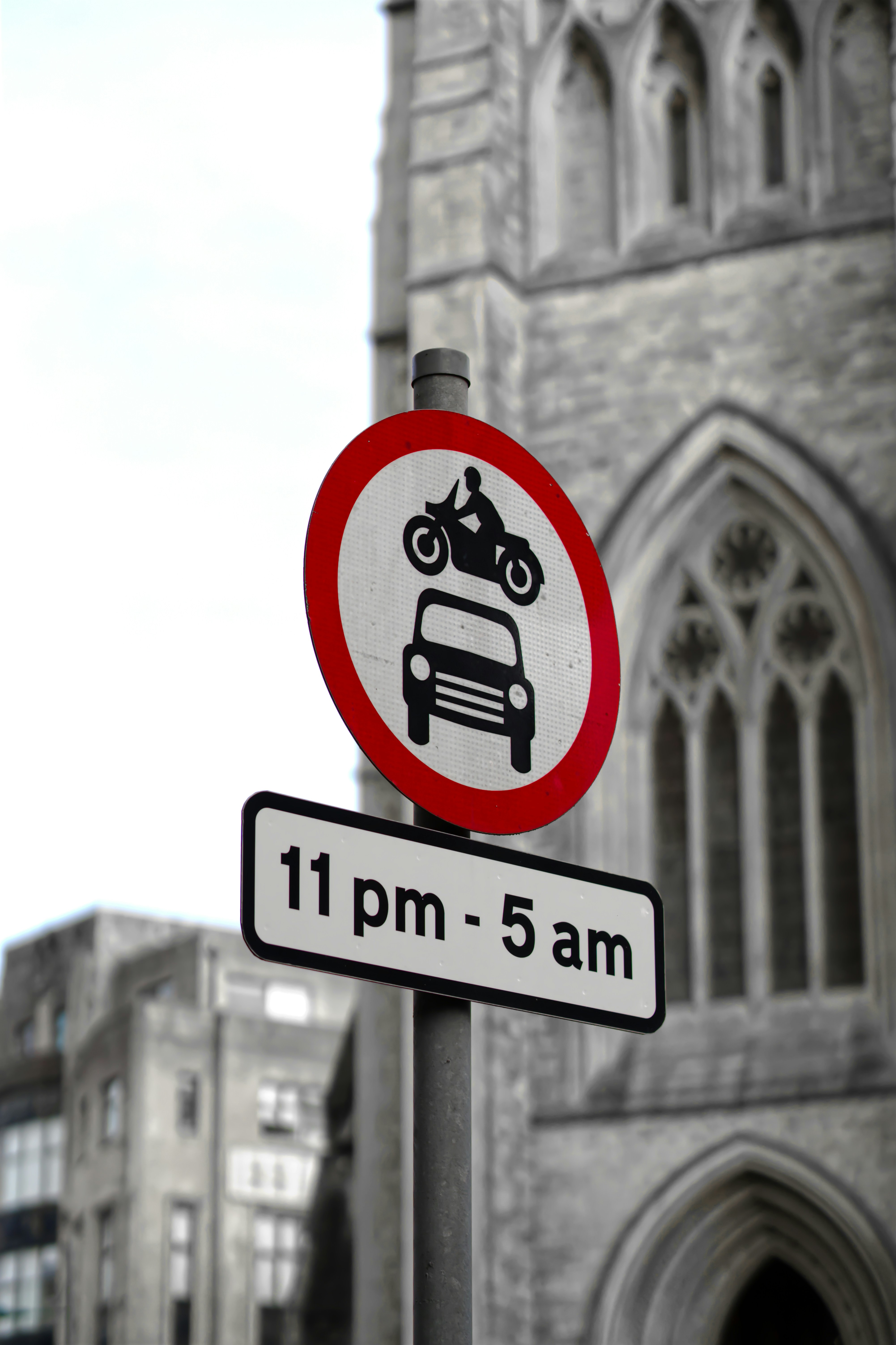 Circle of Caution: Motorcycle-Car Sign Framed by Gothic Street Façade