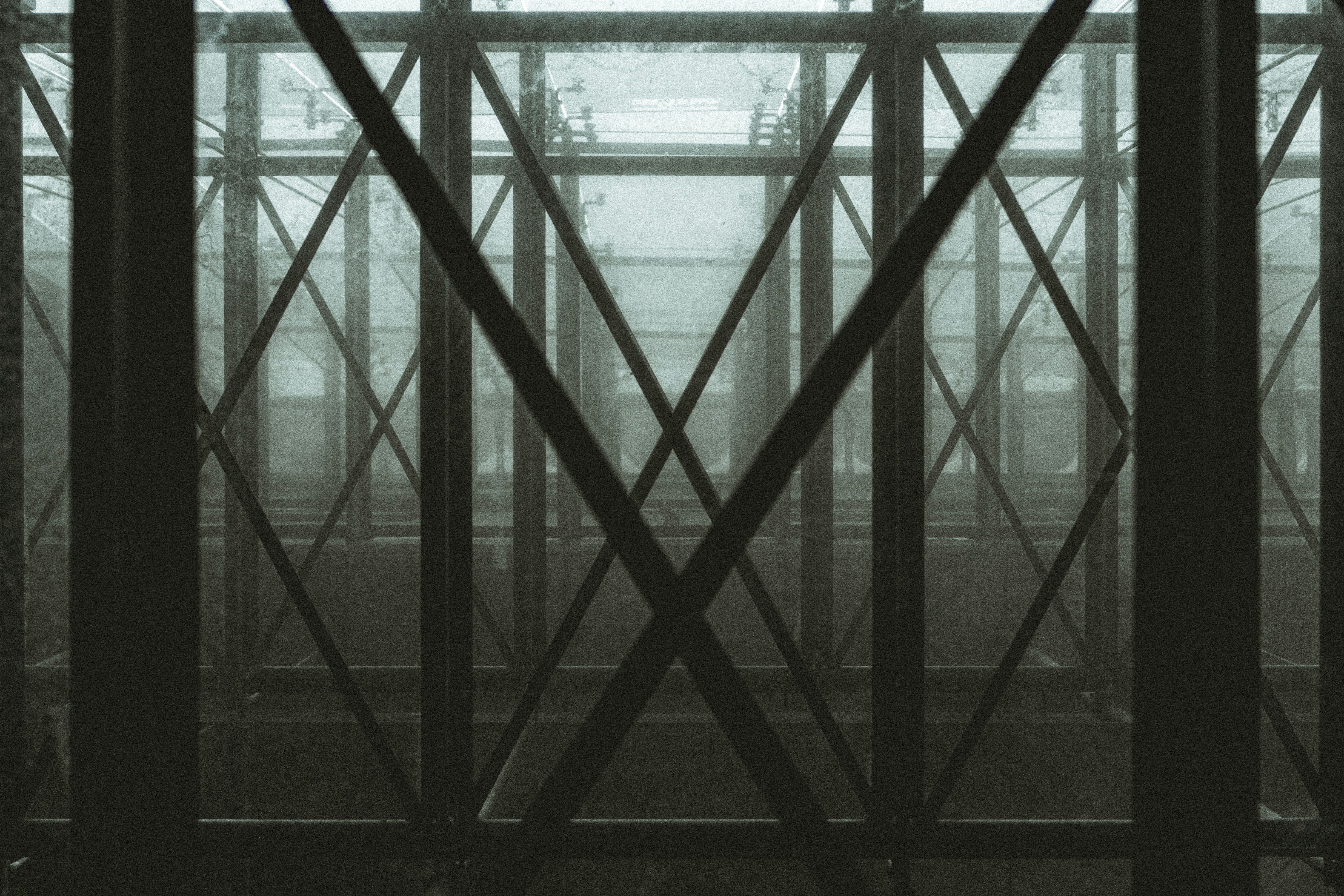 Geometric metal scaffolding creates a layered, symmetrical pattern through a misty atmosphere.