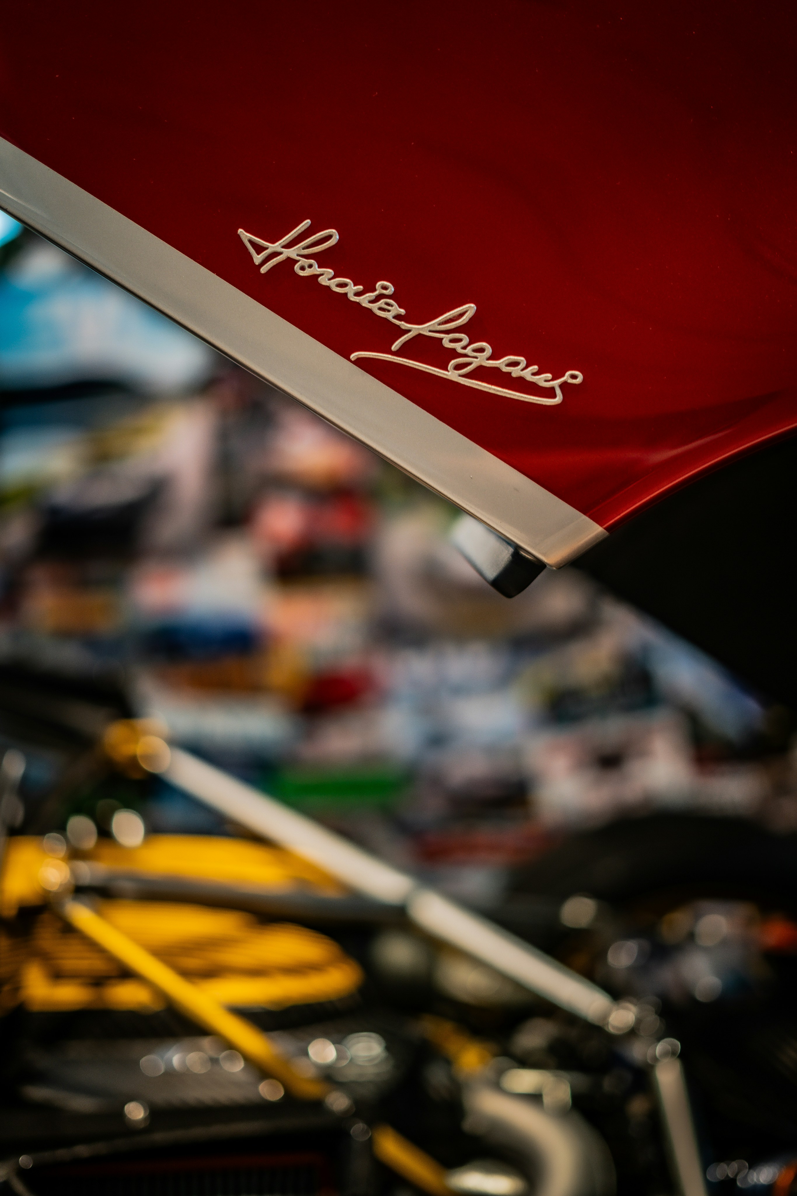 Crimson Script Emblem on a Red Car Hood with a Blurred Workshop Backdrop