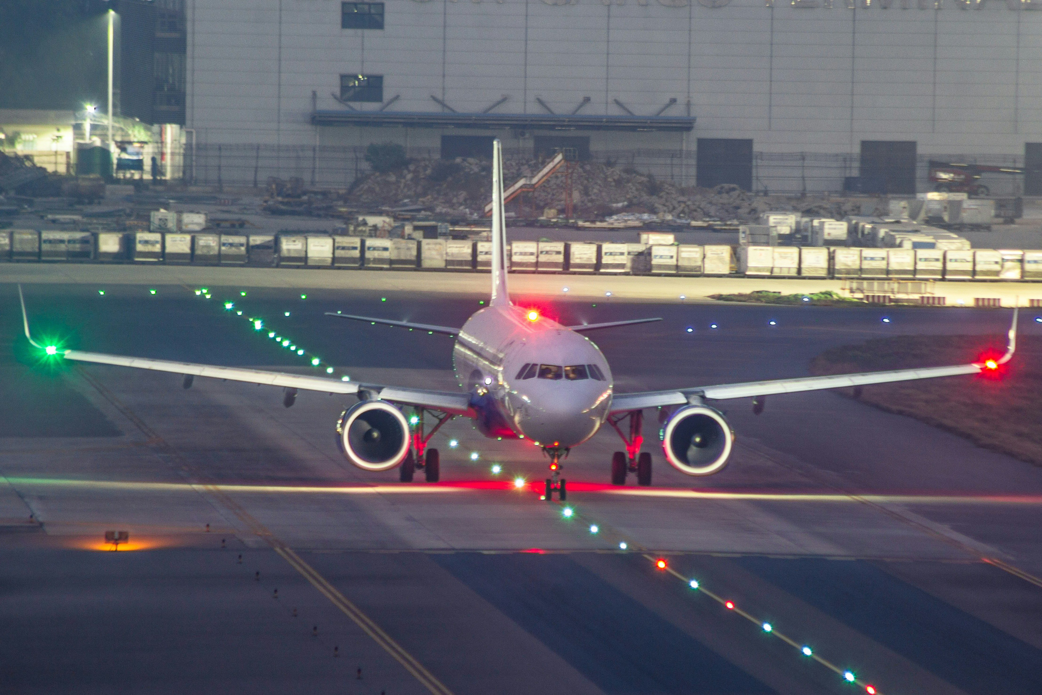 Airbus A320 on a runway with navigation lights aglow during dusk.