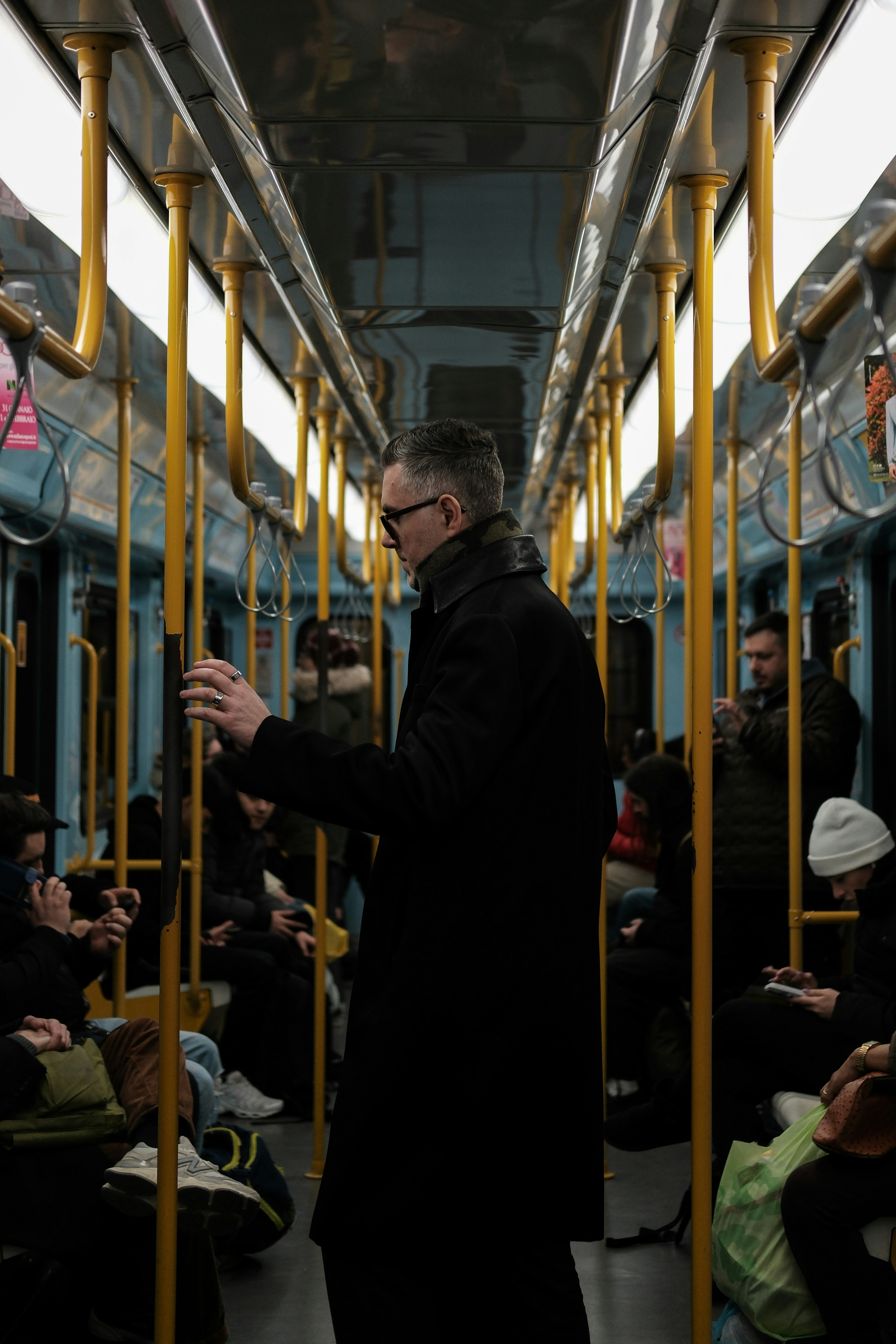 A man in a black coat standing on a train