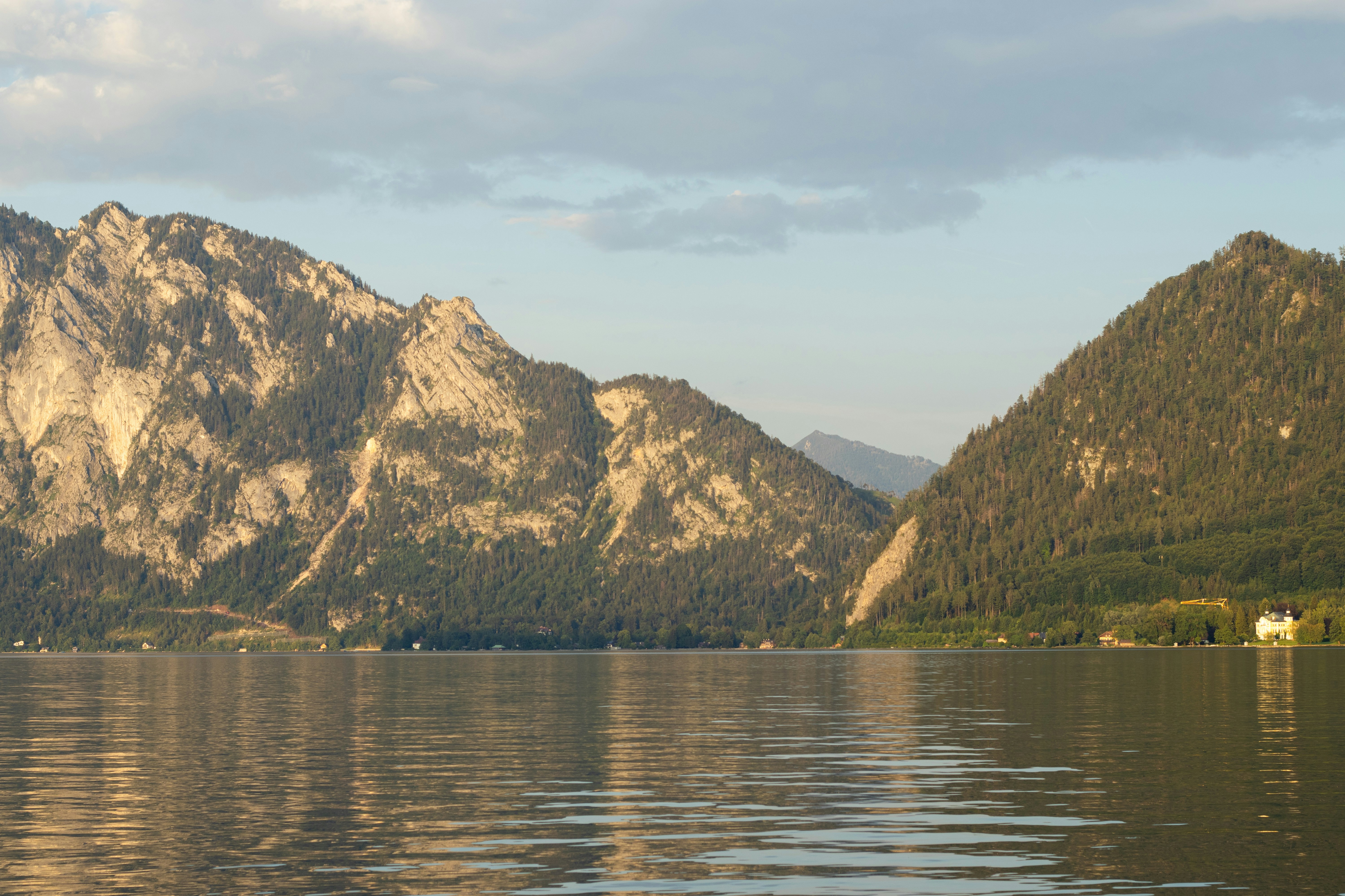 Serene lake with mountain reflections under a partly cloudy sky.
