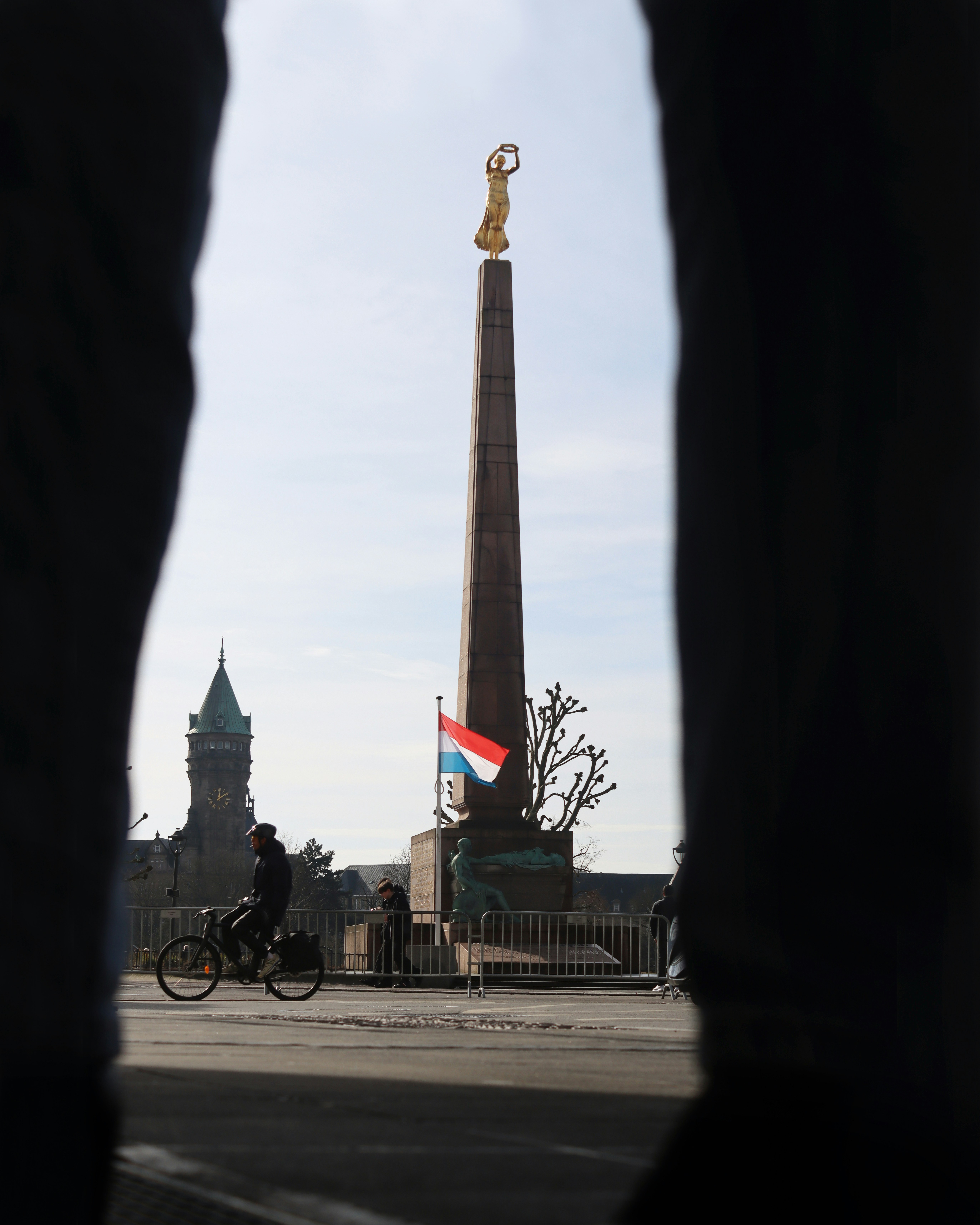 A person riding a bike past a tall obelisk