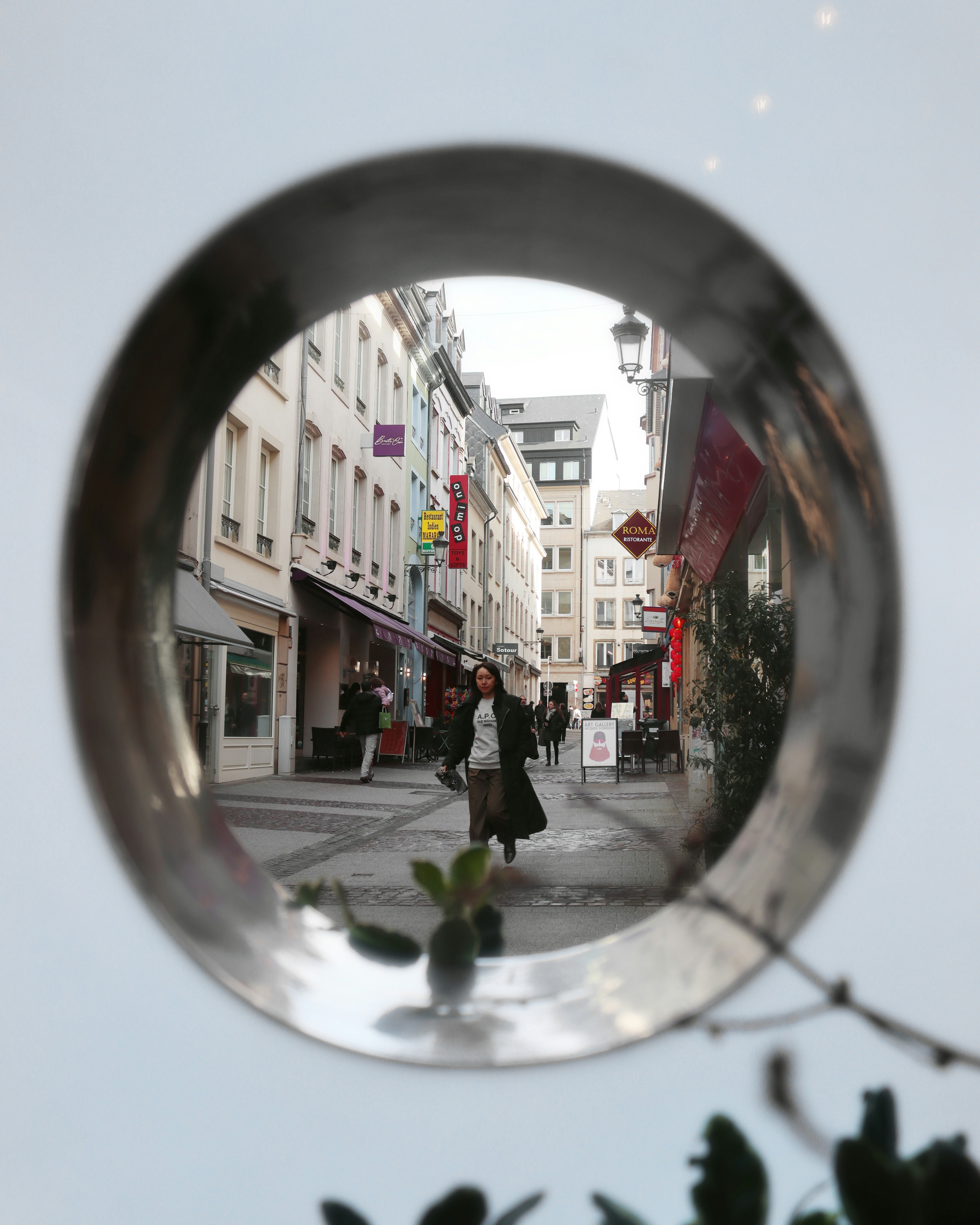 Through the Circular Frame: Pedestrian in a Shallow Street of Shops
