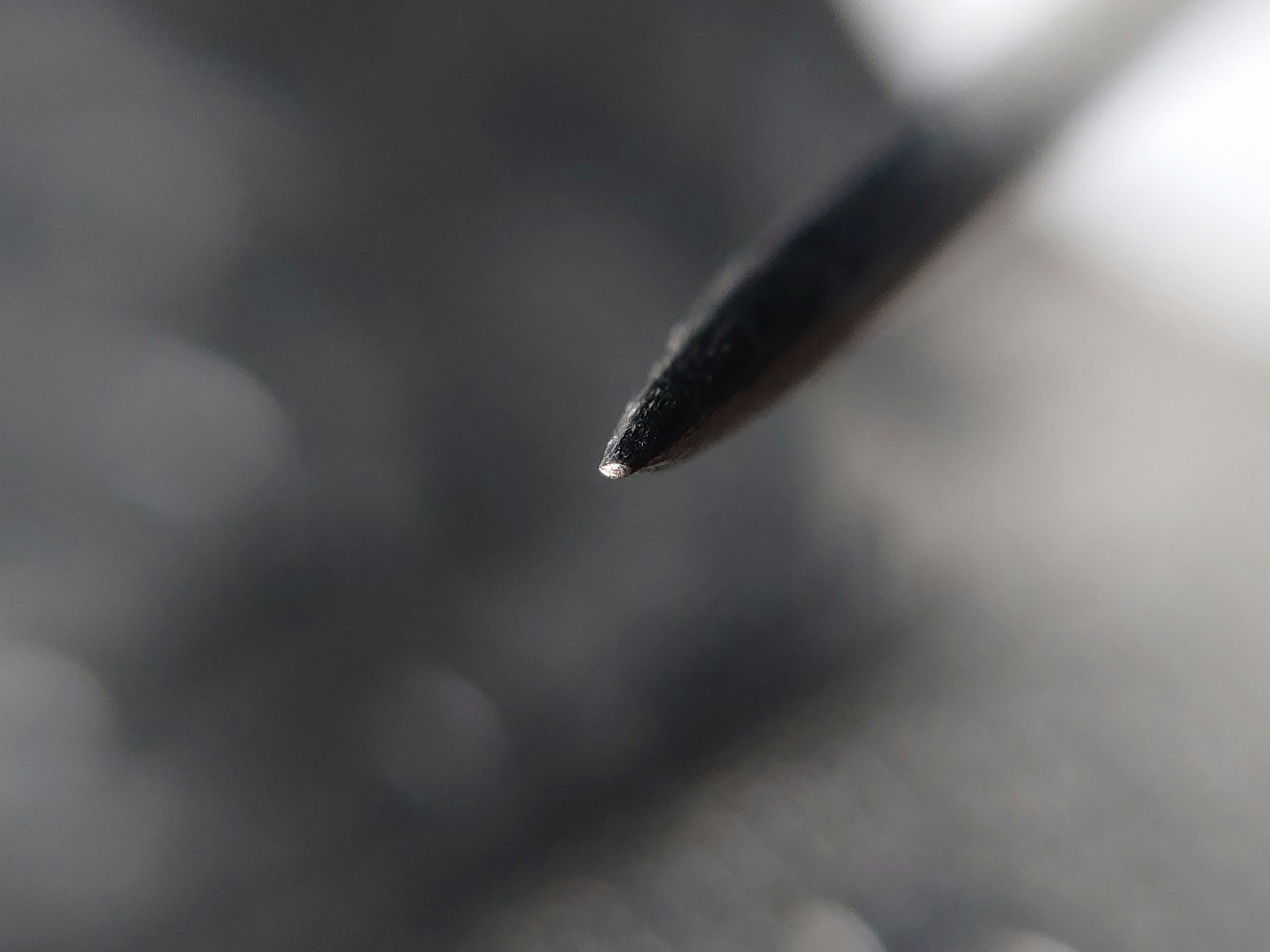 Close-up of a sharpened pencil tip captured in grayscale macro with a soft, blurred background.