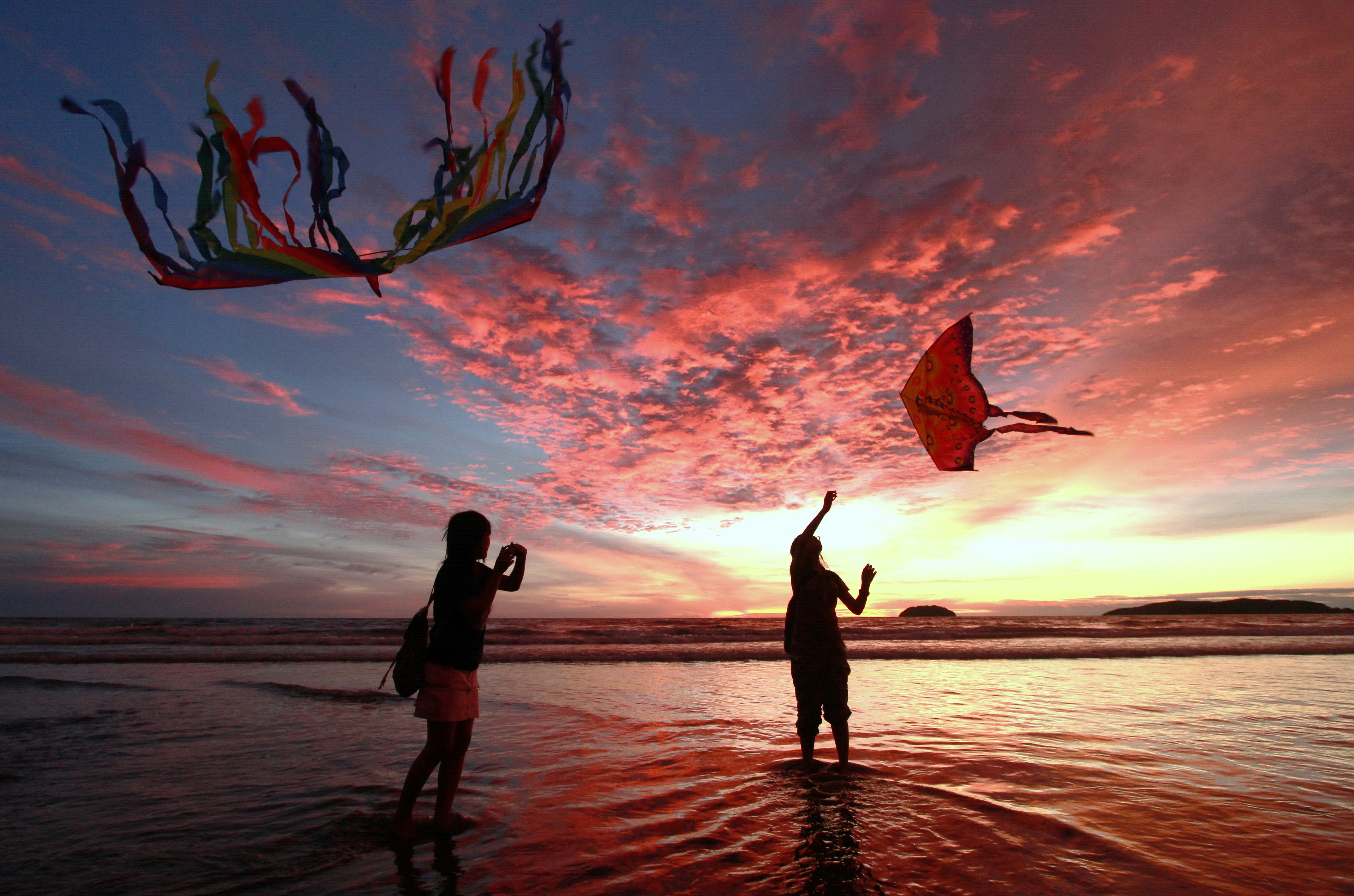 A couple of people flying a kite on top of a beach photo – Free Beach ...