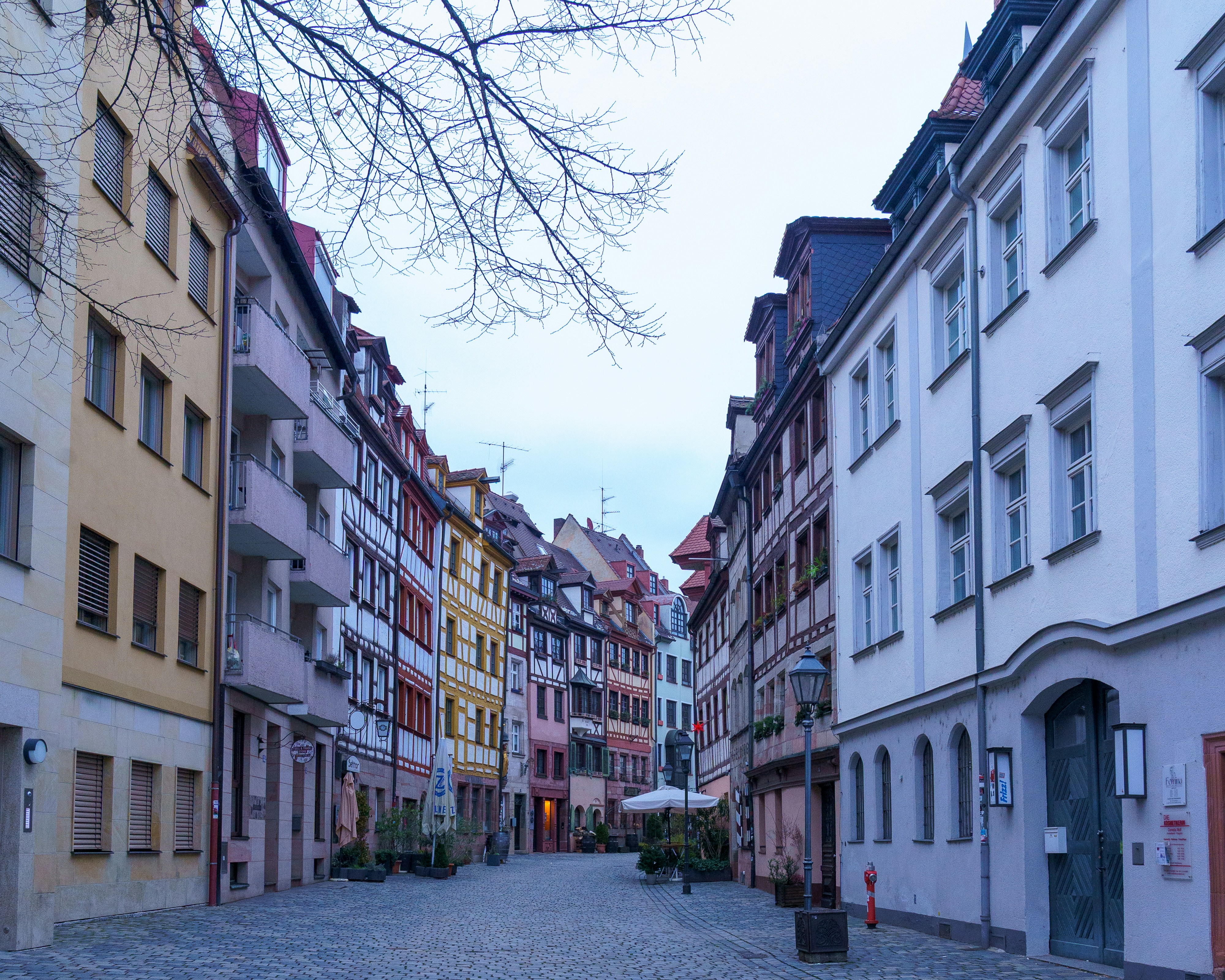 Cobblestone street flanked by colorful historical buildings under a pale sky.