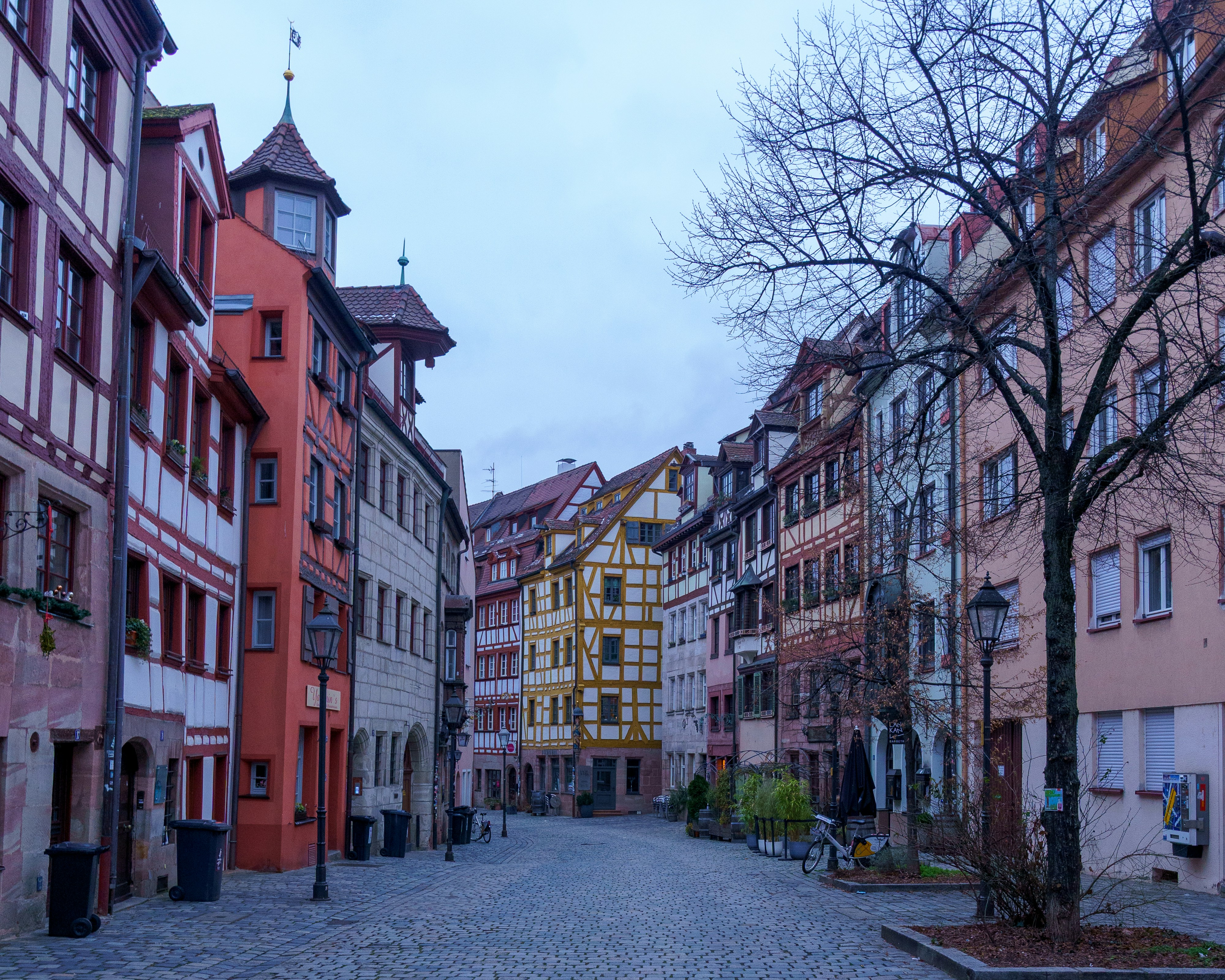 Cobblestone street lined with colorful, historic half-timbered buildings under an overcast sky.