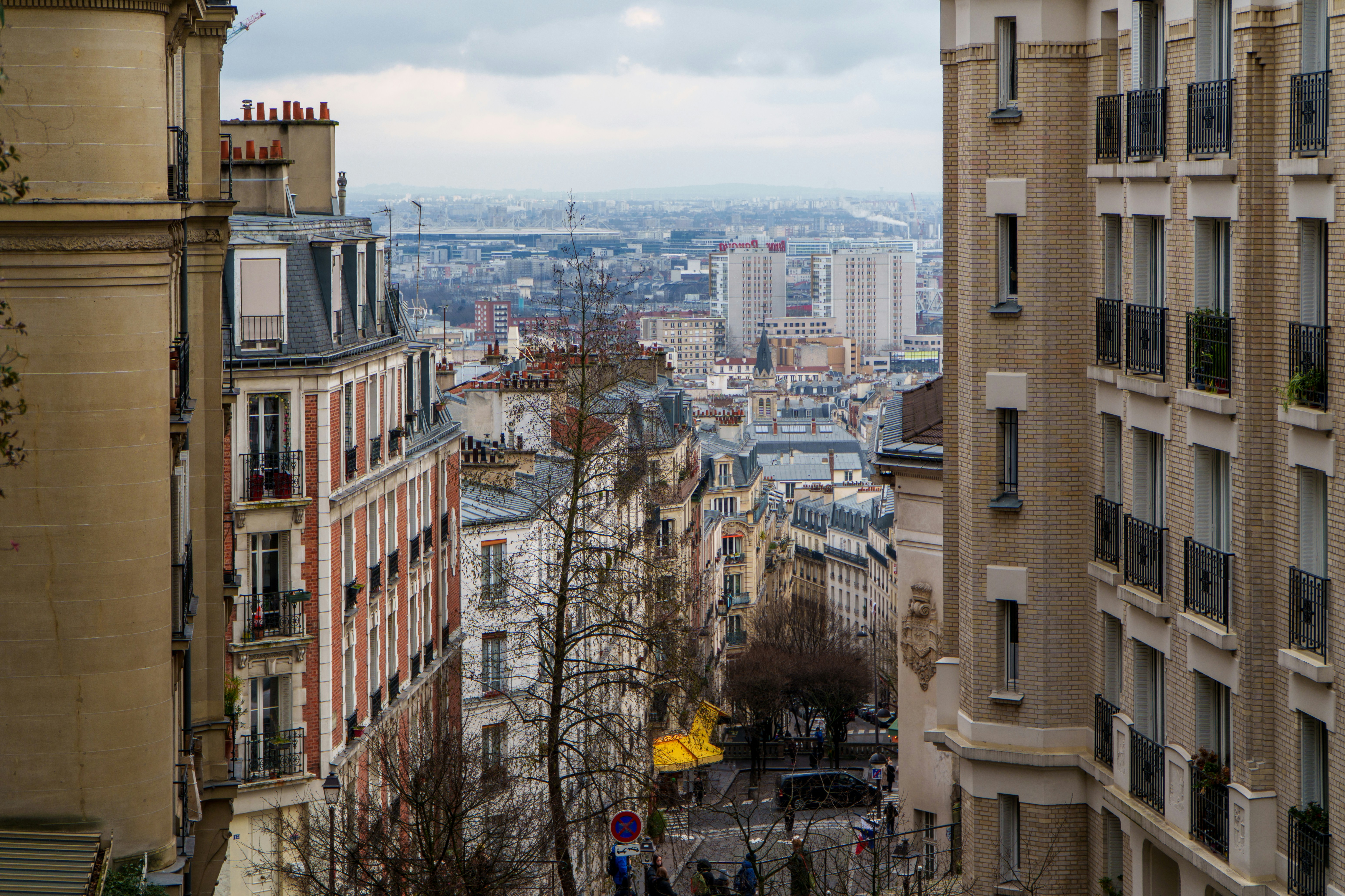 Cityscape framed by classic Parisian buildings and overcast sky.