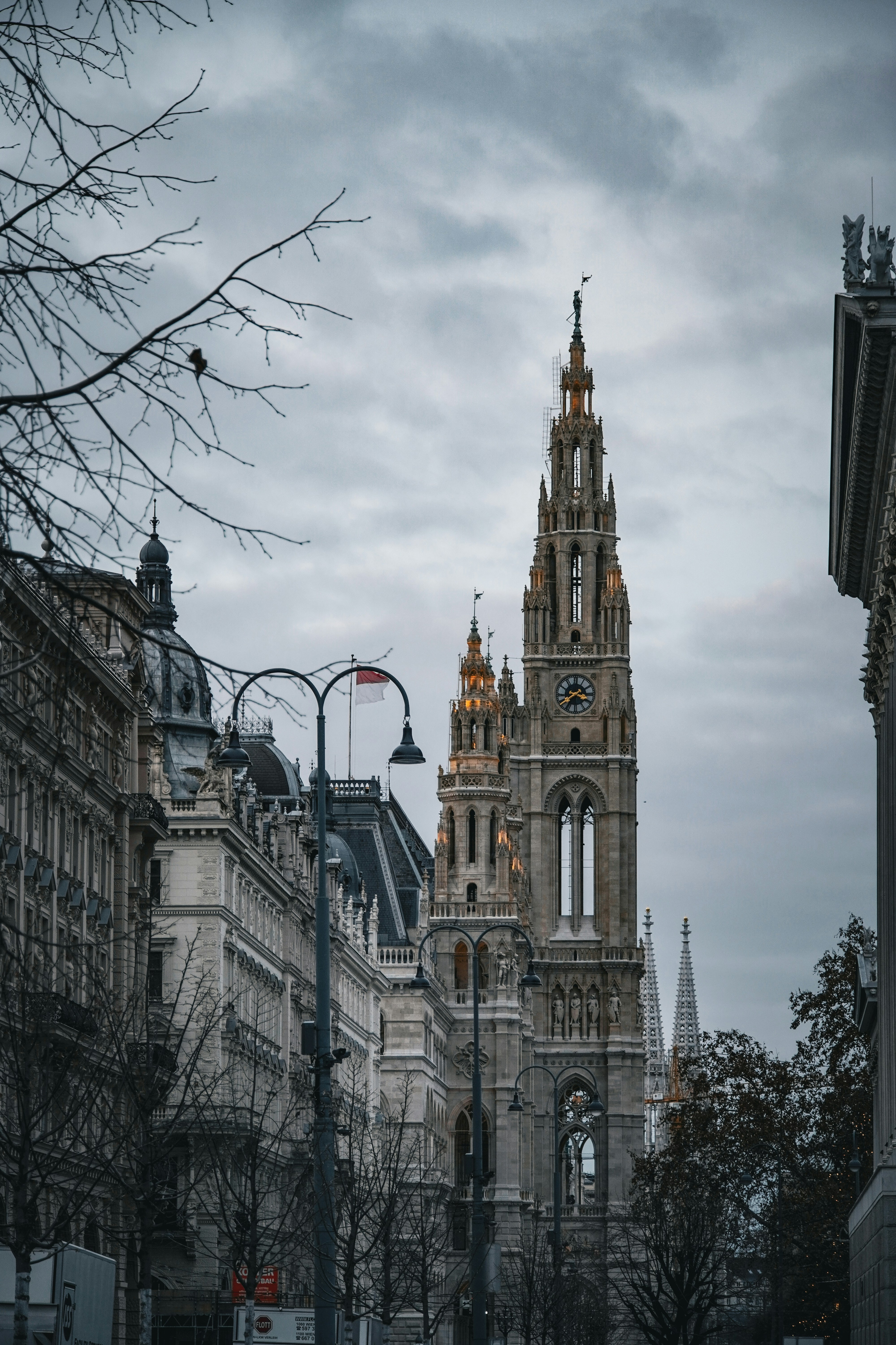 Ornate gothic-style tower rises above surrounding buildings under a cloudy sky.