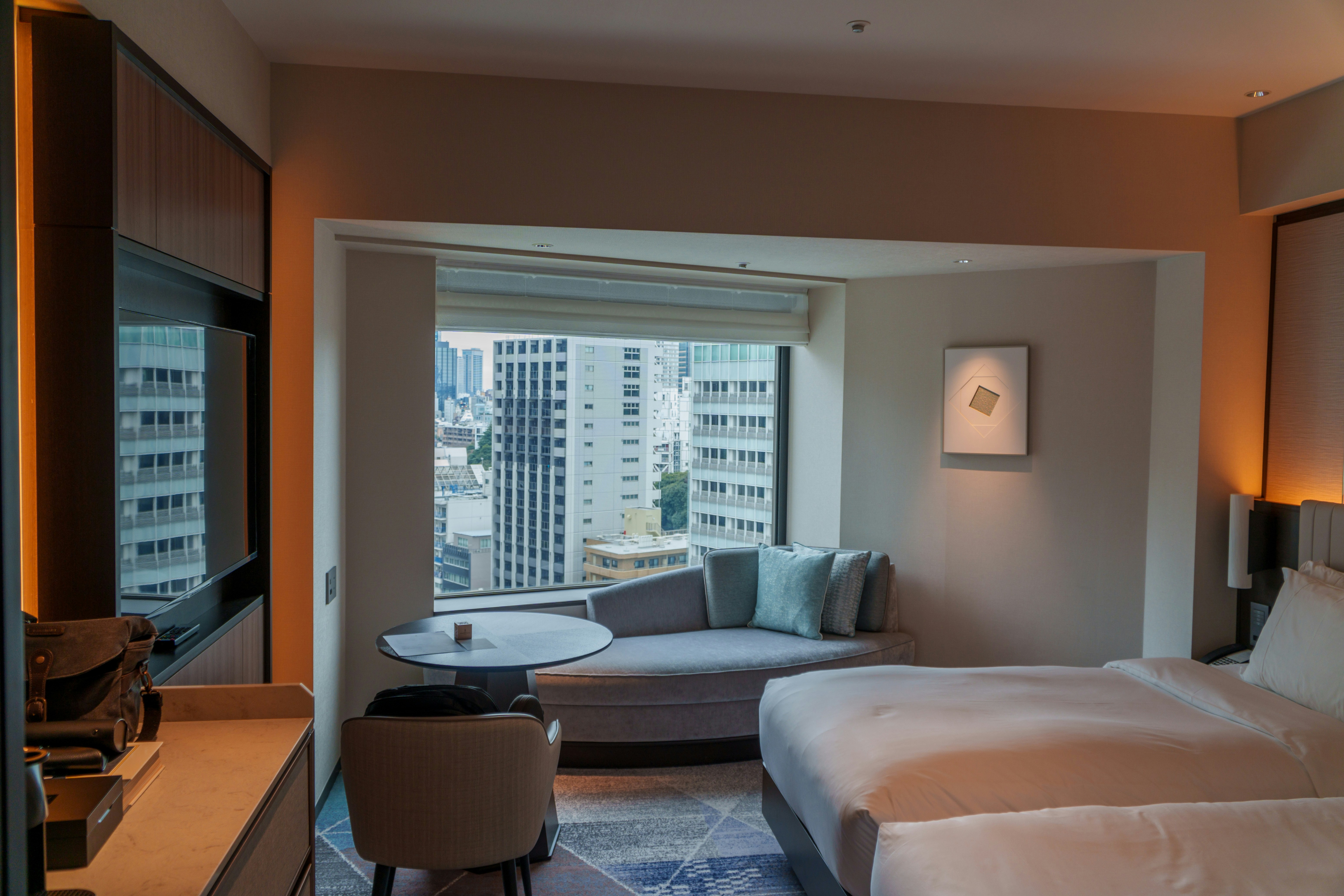 Contemporary hotel room with city view, modern furnishings, and ambient lighting.