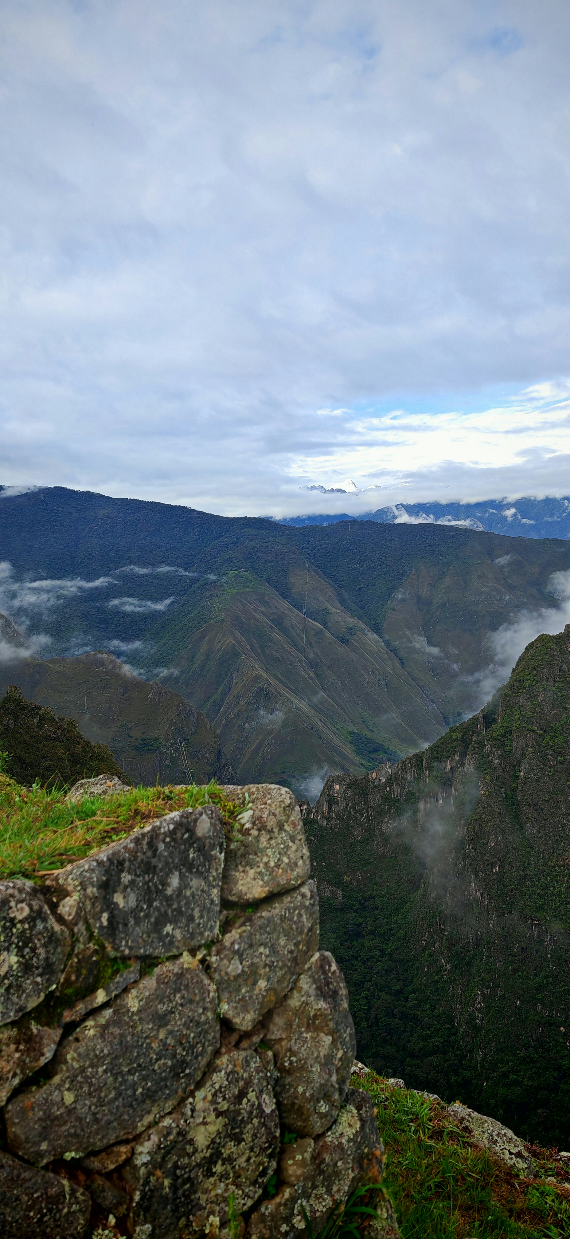 Stone ruins overlooking misty mountain valleys under a cloud-filled sky.