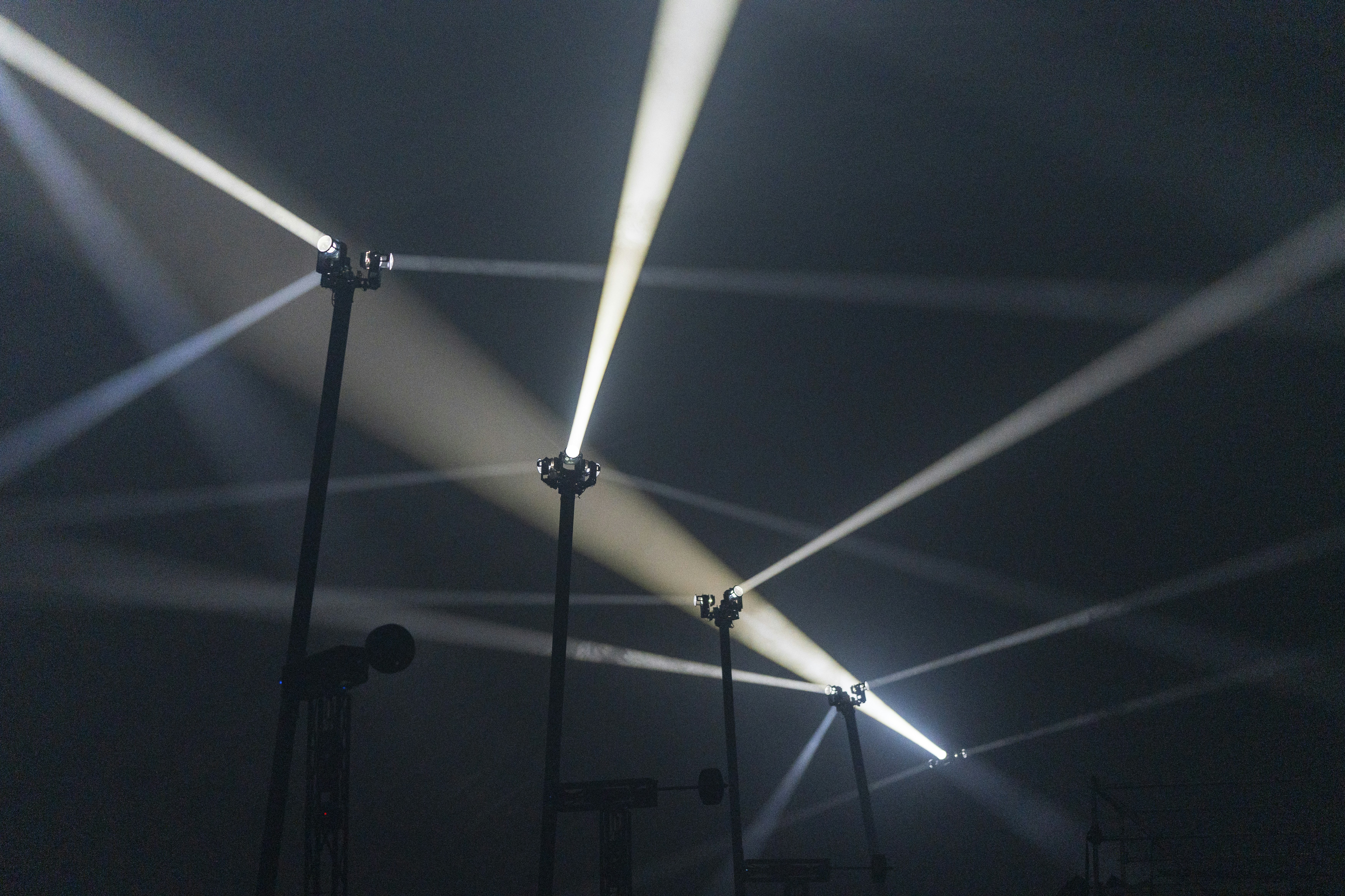 Beams of light crisscross through the night sky, creating geometric patterns.