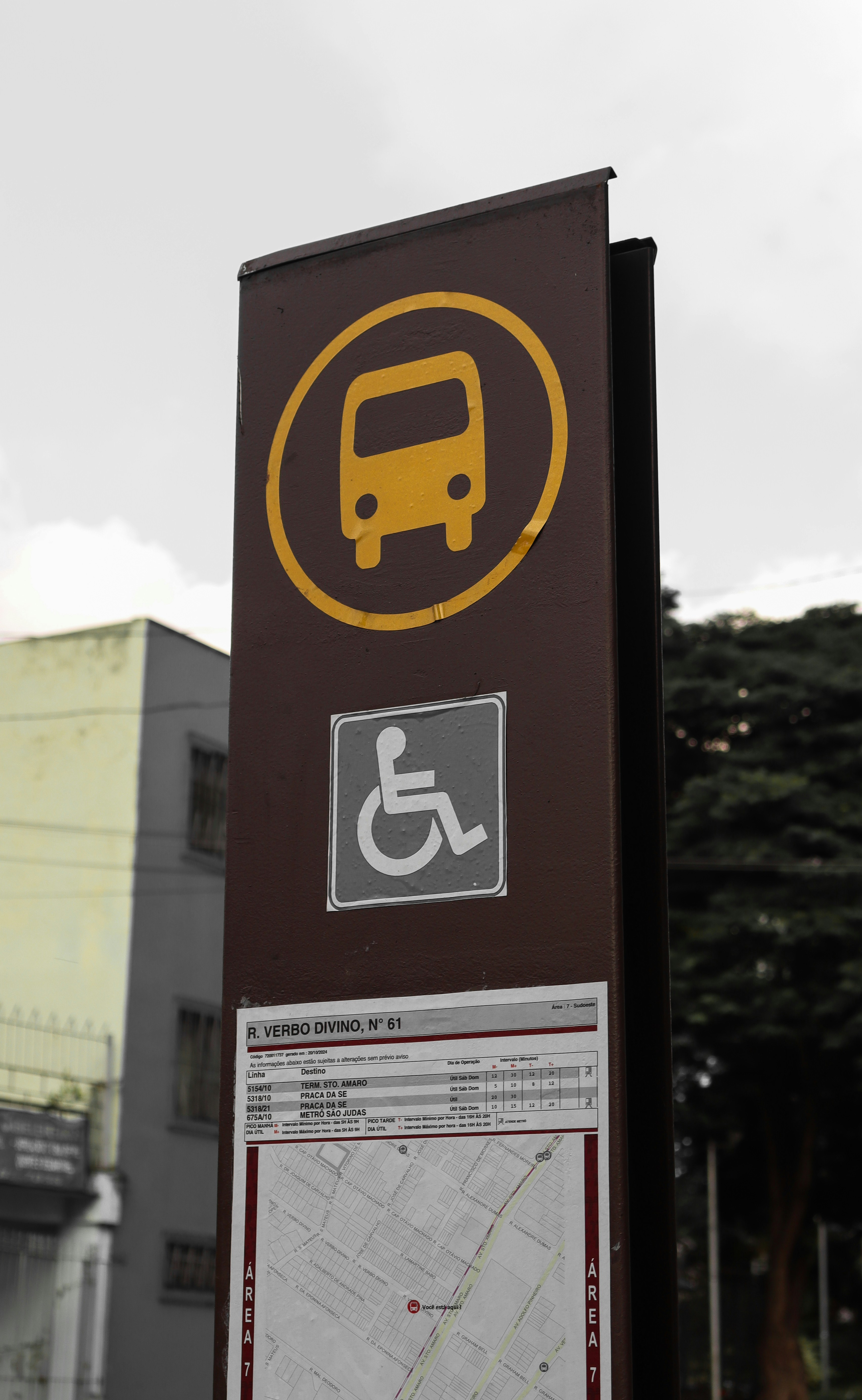 Maroon Transit Sign: Bold Bus Icon and Accessibility Badge Framed by an Urban Map