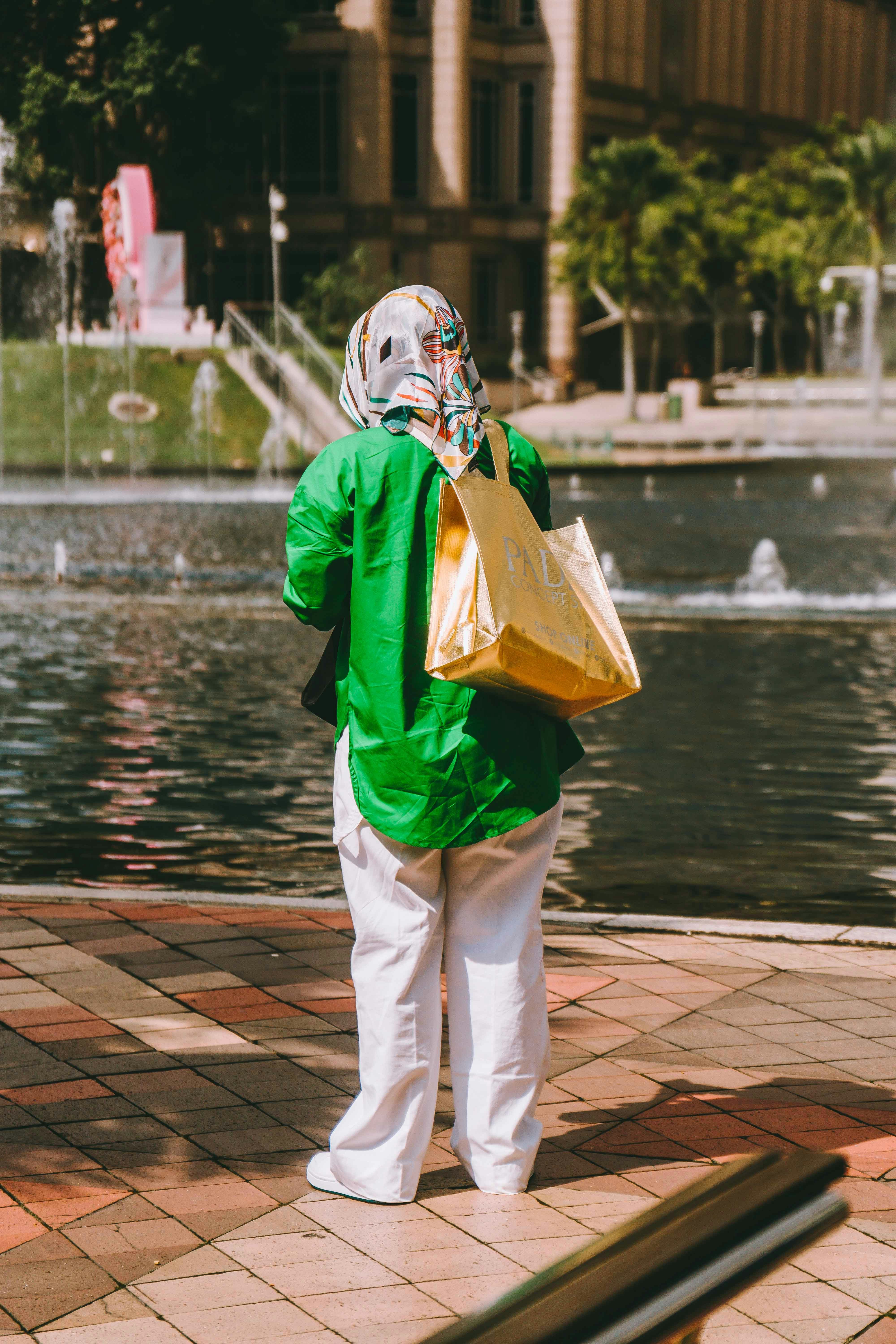 Green Coat by the Fountain: A Quiet Urban Moment with a Golden Tote