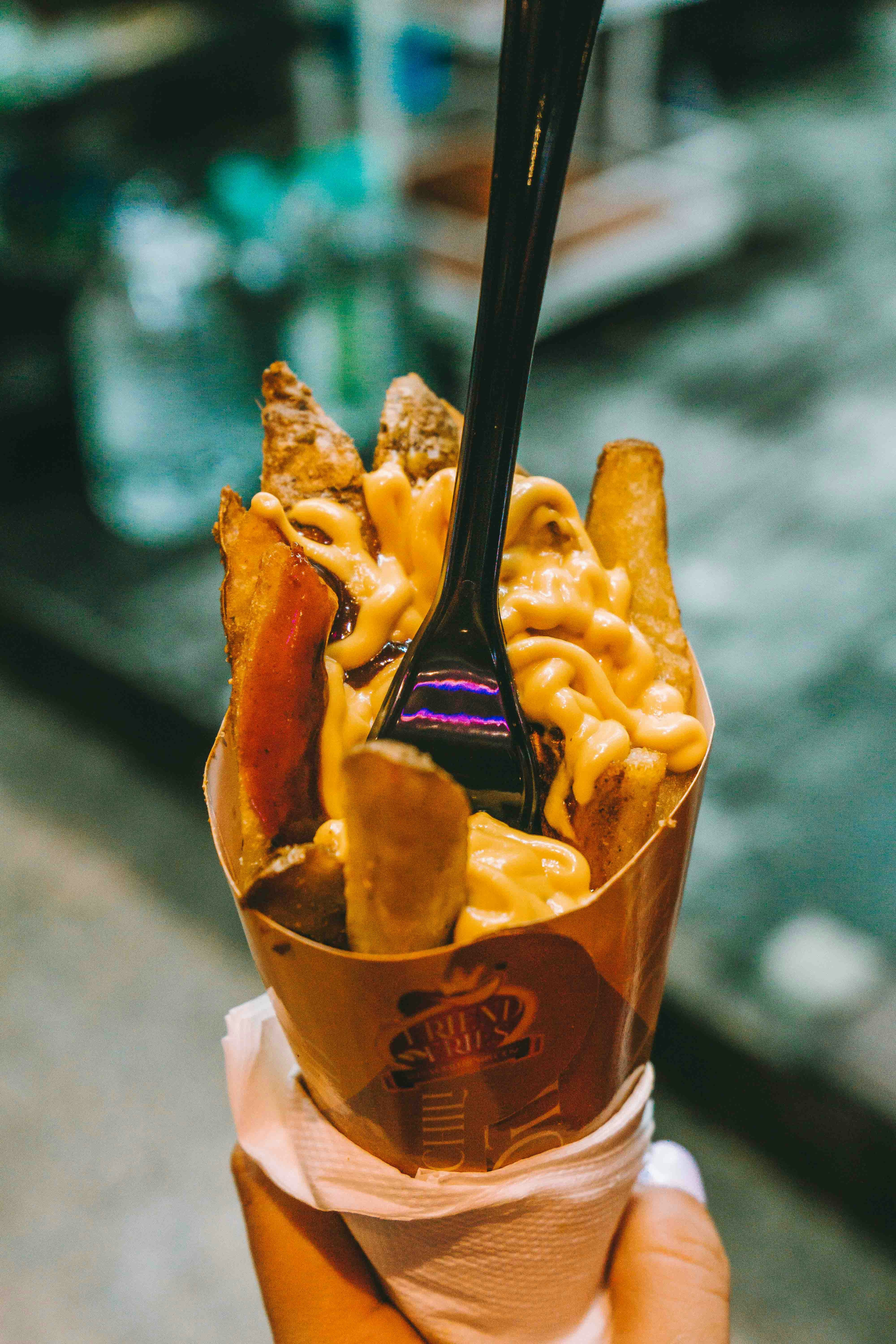 Golden Crunch: Fries, Cheese, and a Drip of Sauce in a Cone