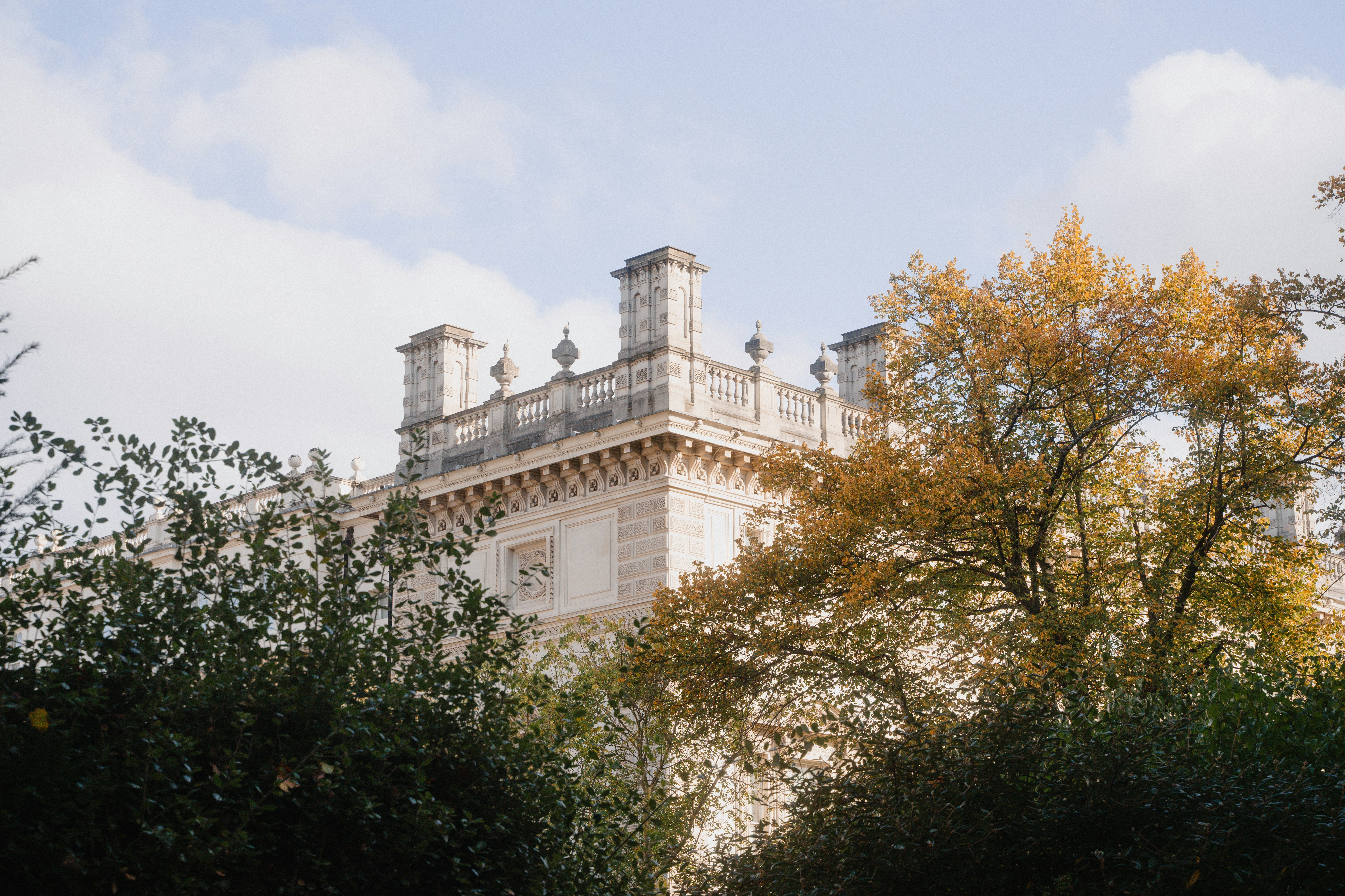 Historic building facade framed by autumn trees under a clear blue sky.