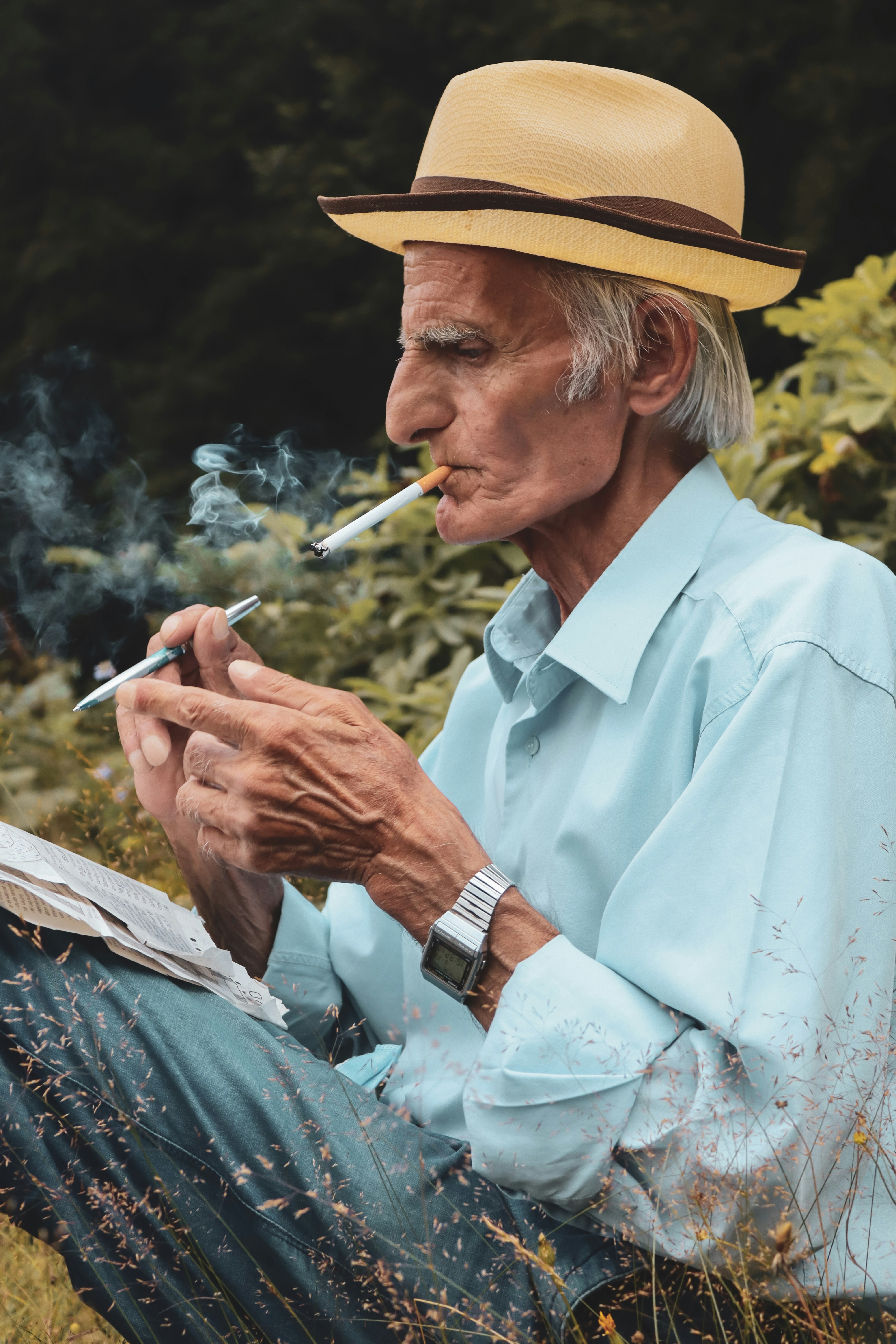 A man sitting in a field smoking a cigarette photo – Free Face Image on ...