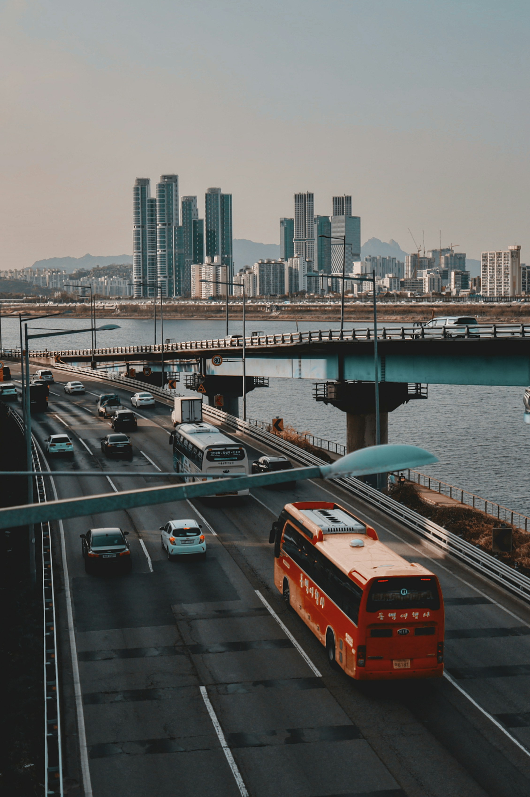 A red bus driving down a street next to a bridge photo – Free City ...