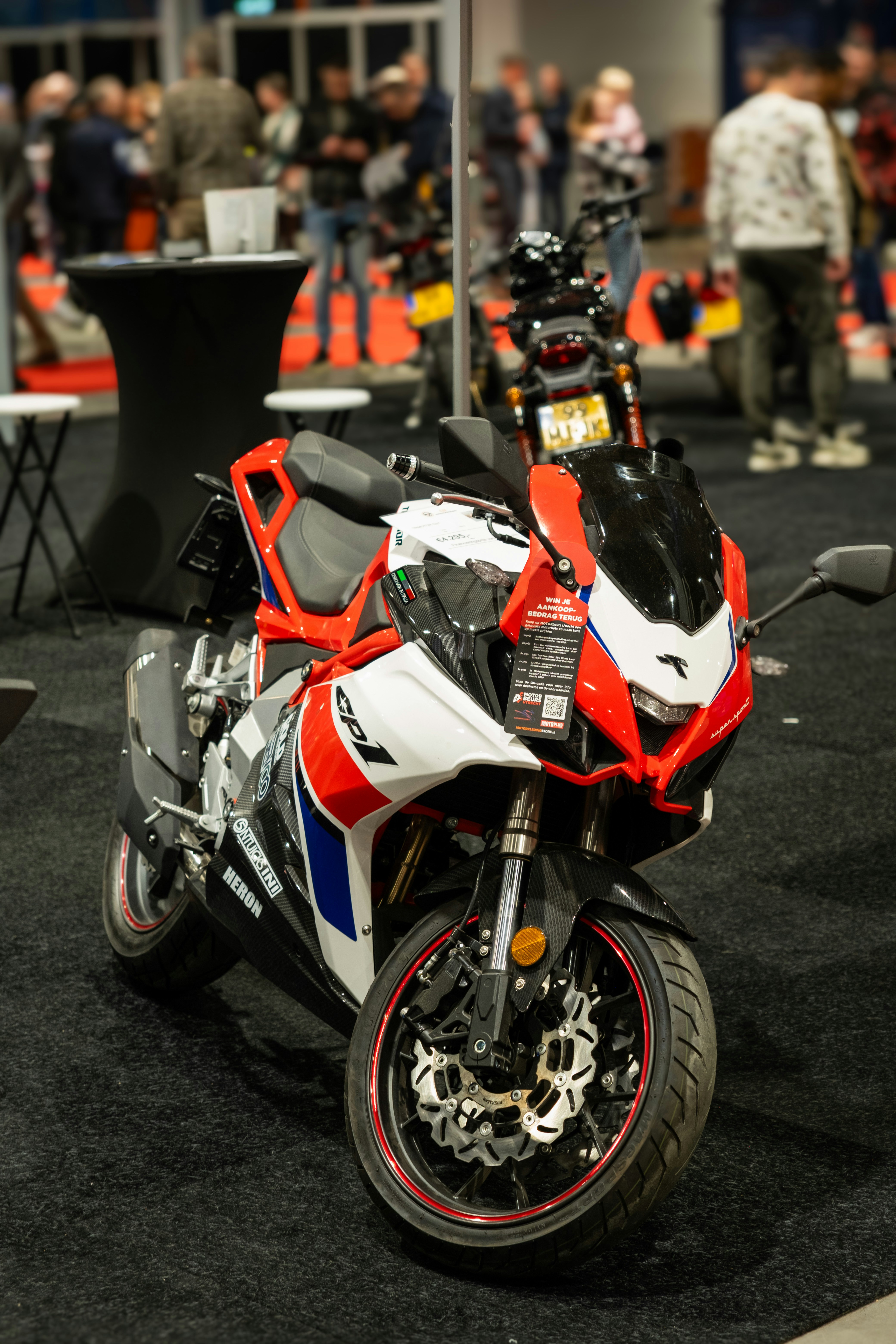 A red, white and blue motorcycle on display at a convention photo ...