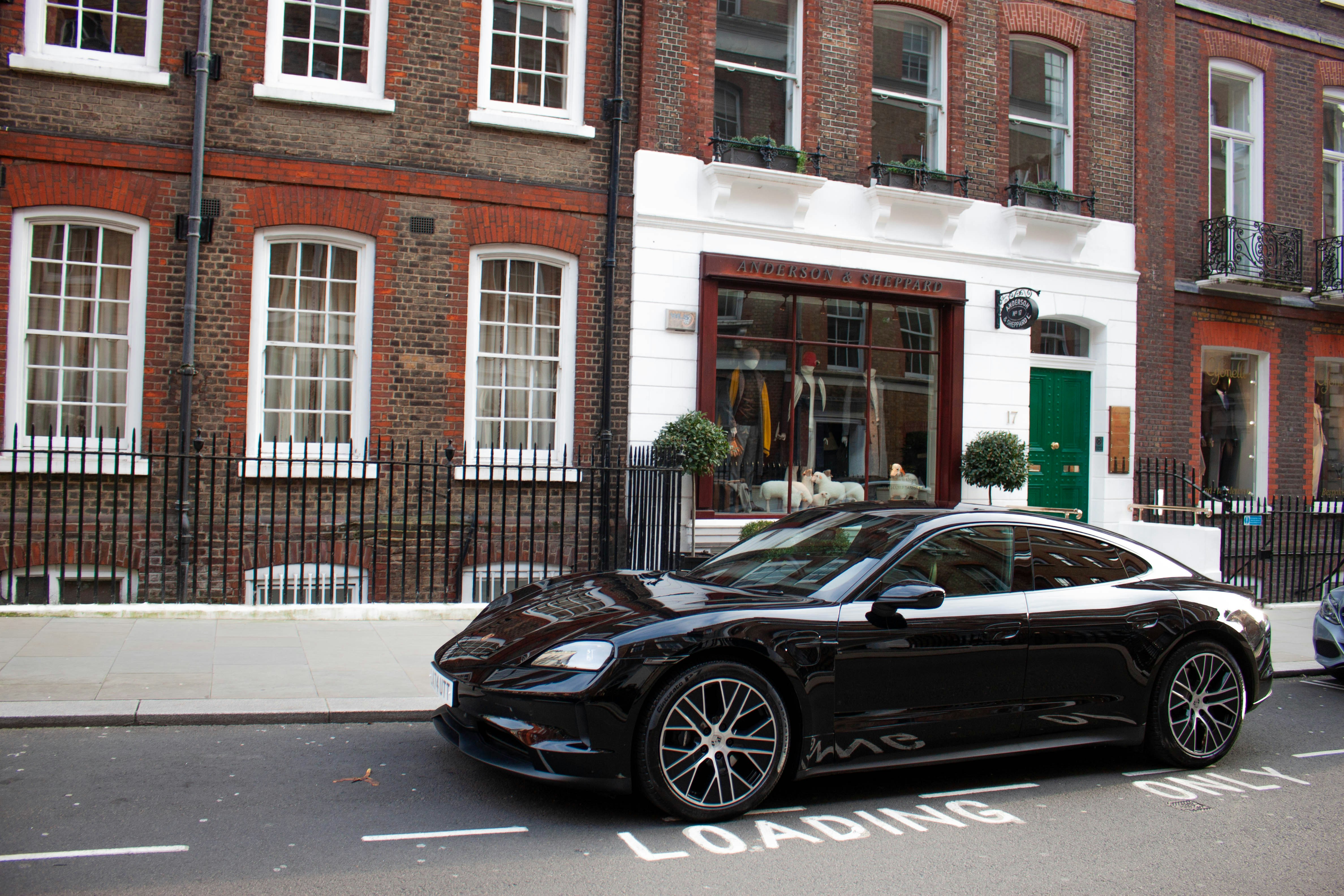 Black sports car parked in front of a traditional red brick building with large windows.