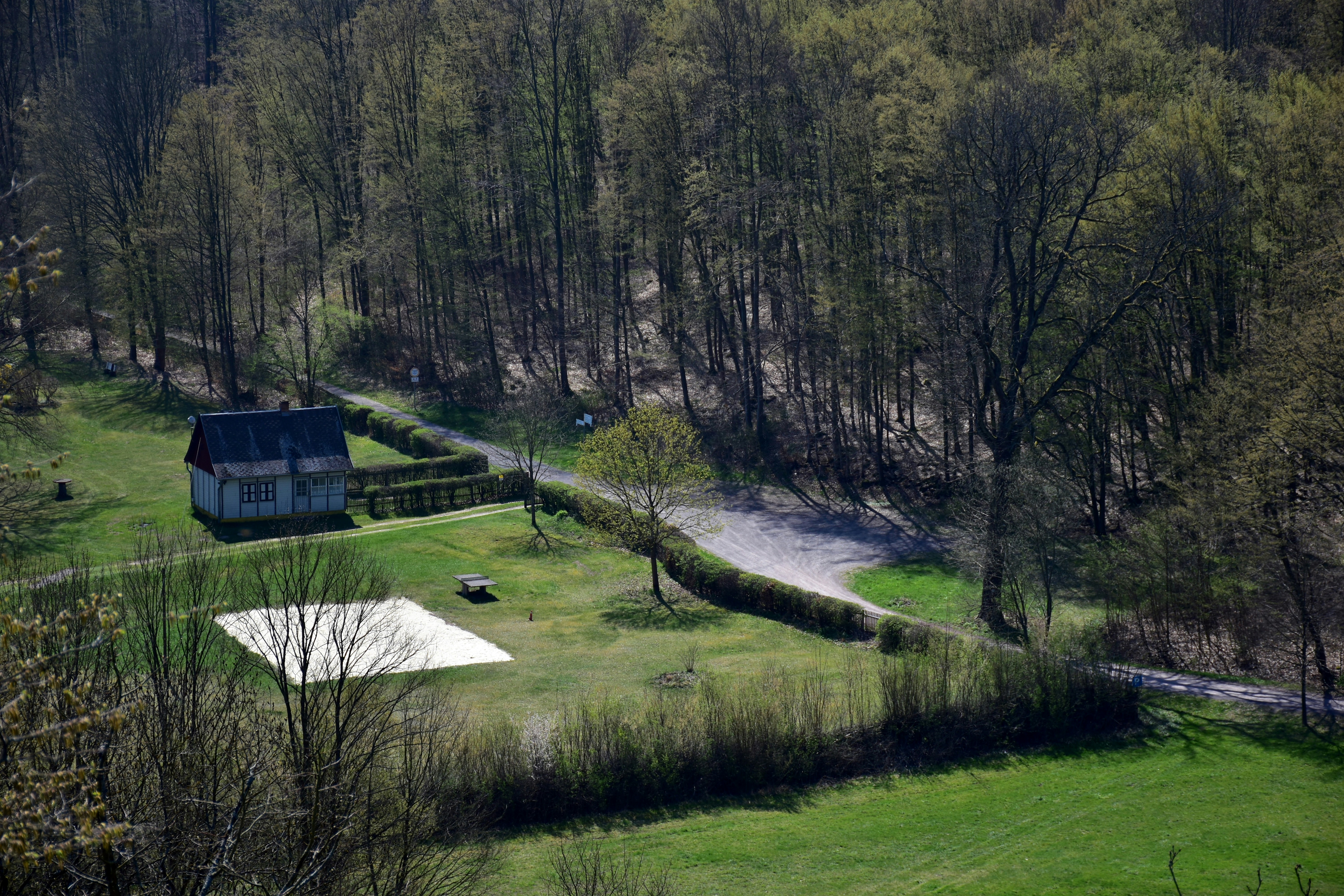 Small house nestled in a lush valley surrounded by dense forest and open fields.