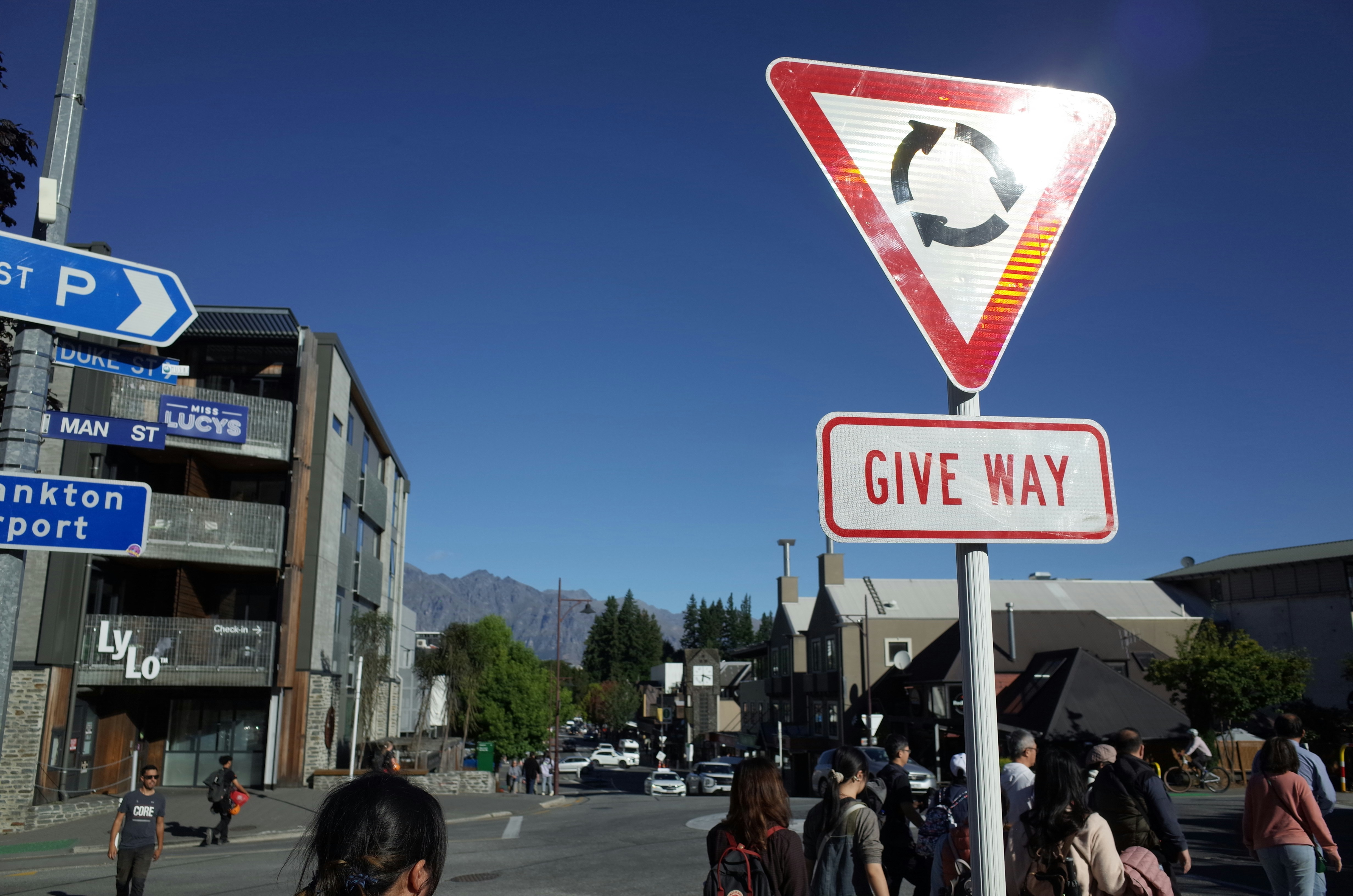 A group of people walking down a street next to a street sign photo ...