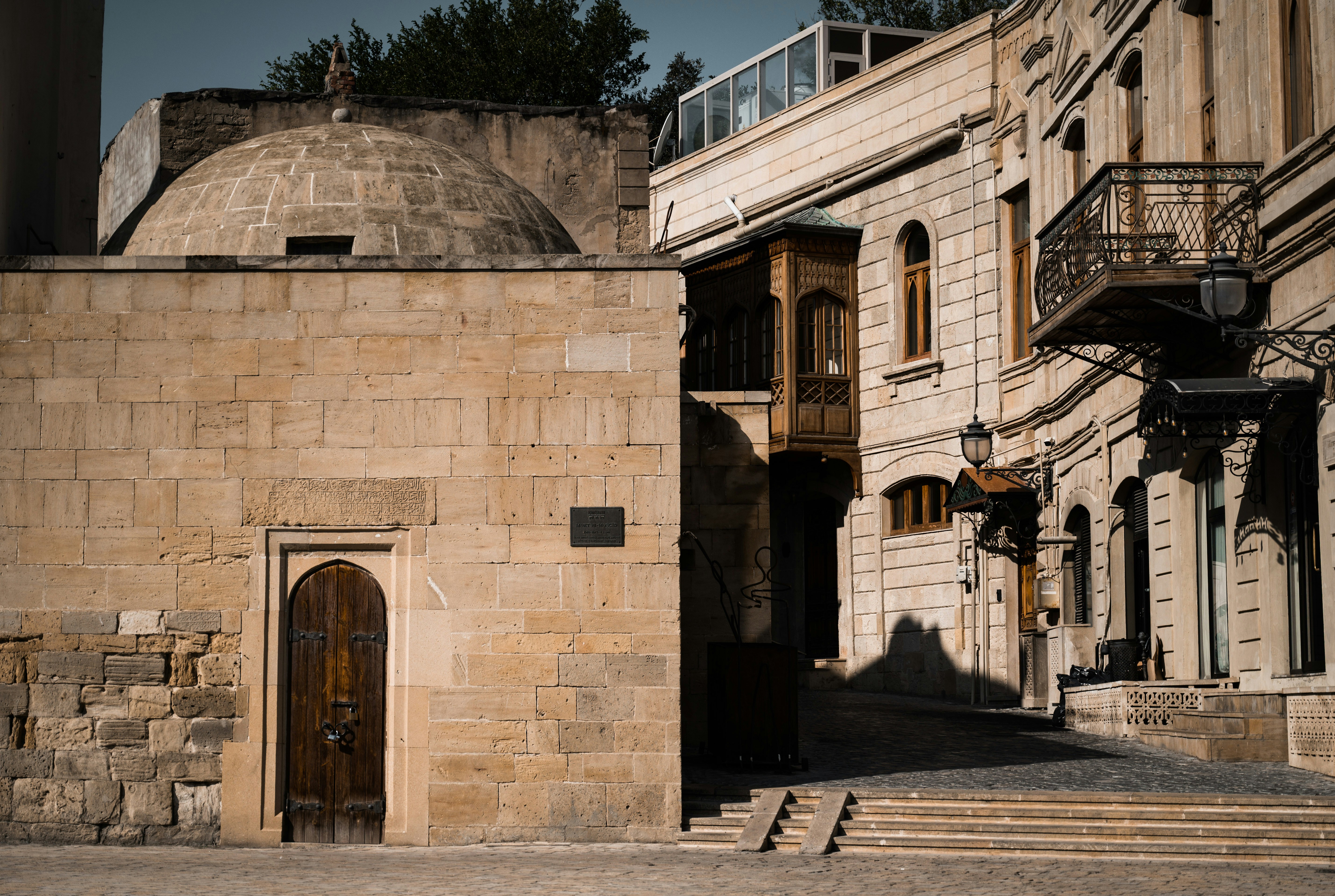 Stone buildings with intricate wooden balconies in Baku's old town under soft afternoon light.