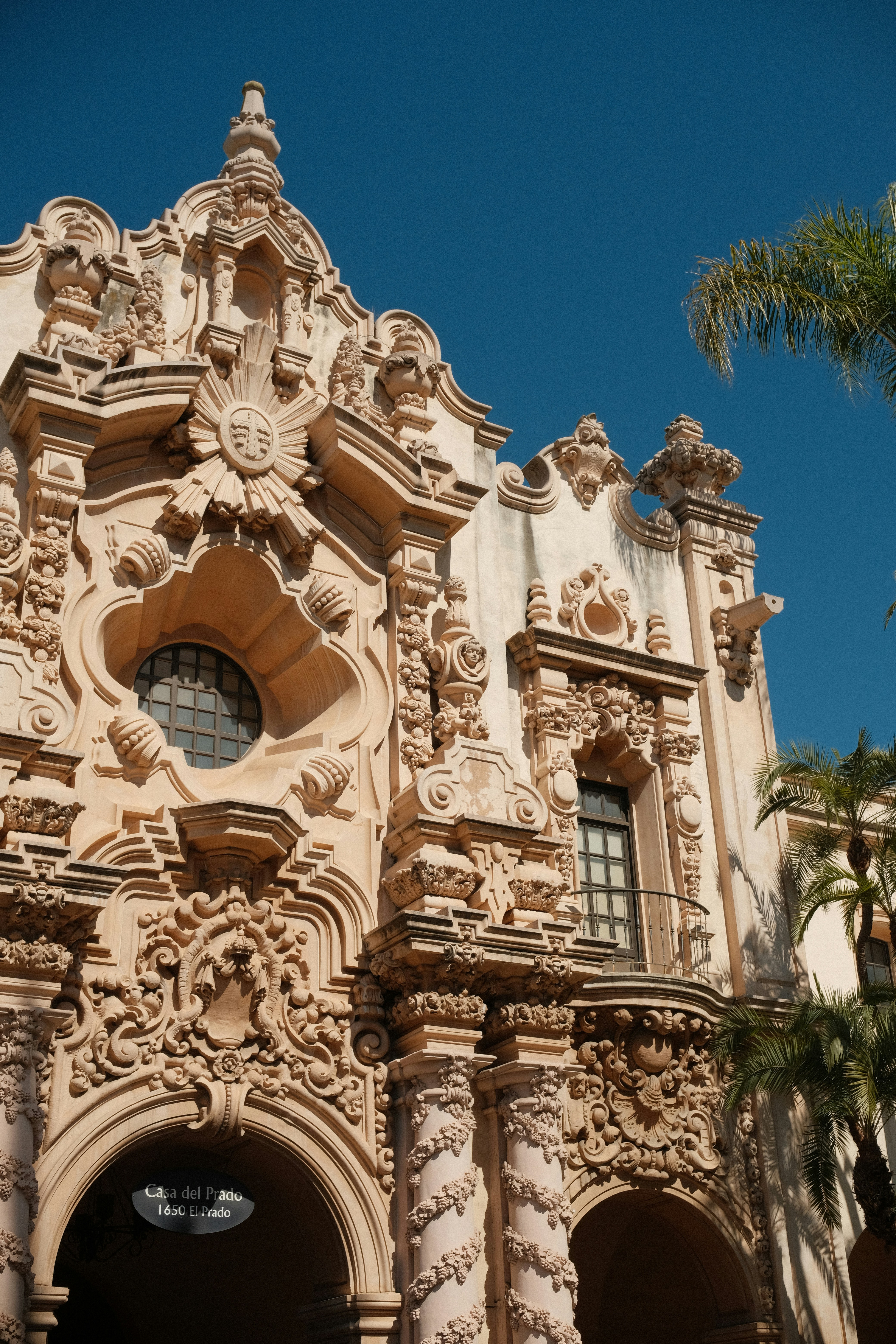 Sunlit Rococo Facade: Intricate Carvings and Palm Shadows