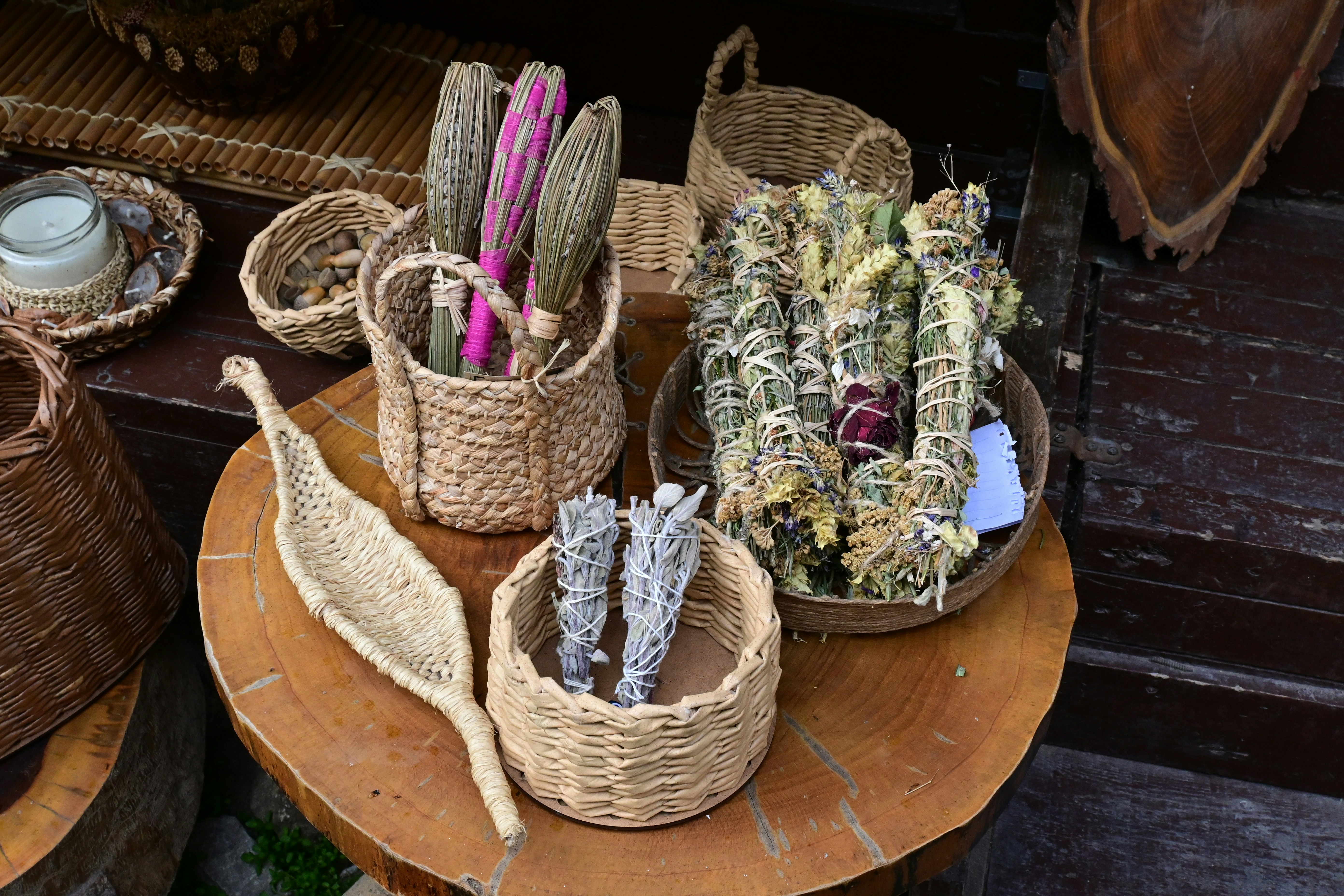 Handcrafted baskets and dried herbs displayed on a wooden table in a traditional bazaar setting.