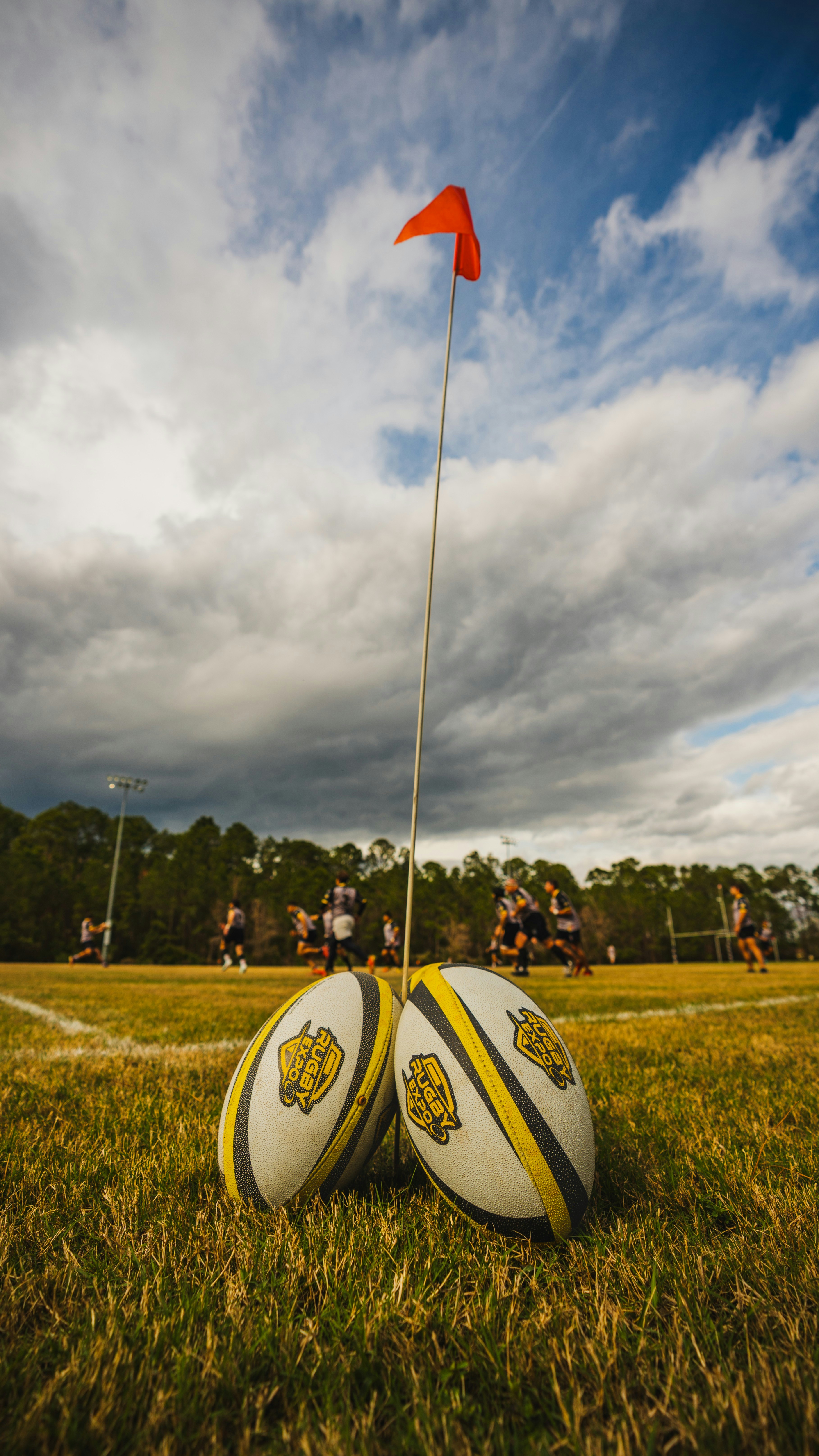 Ground-Level Pulse: Two Rugby Balls at the Flag's Base