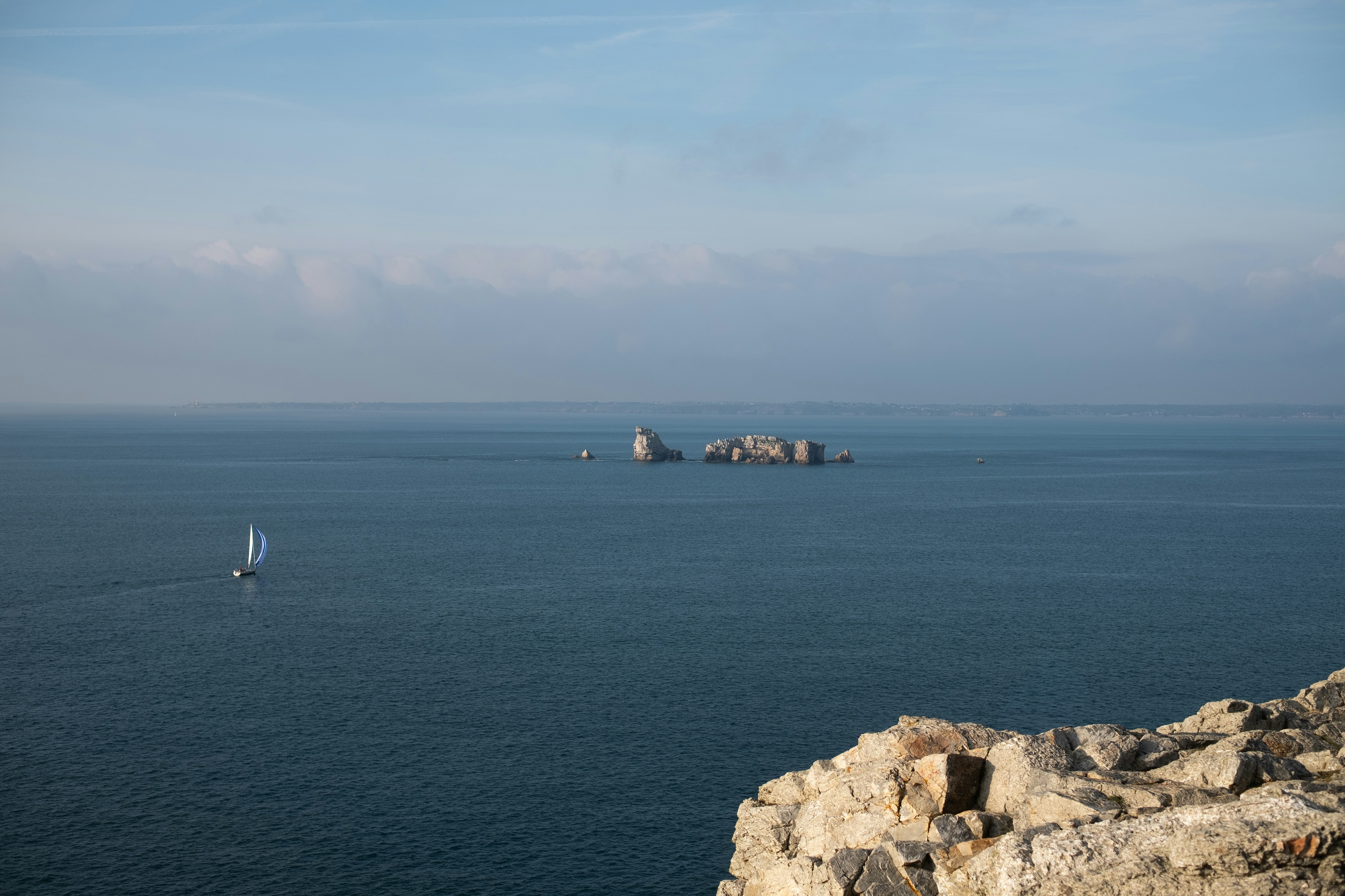 Rocky promontory gazing over a calm sea with a distant island