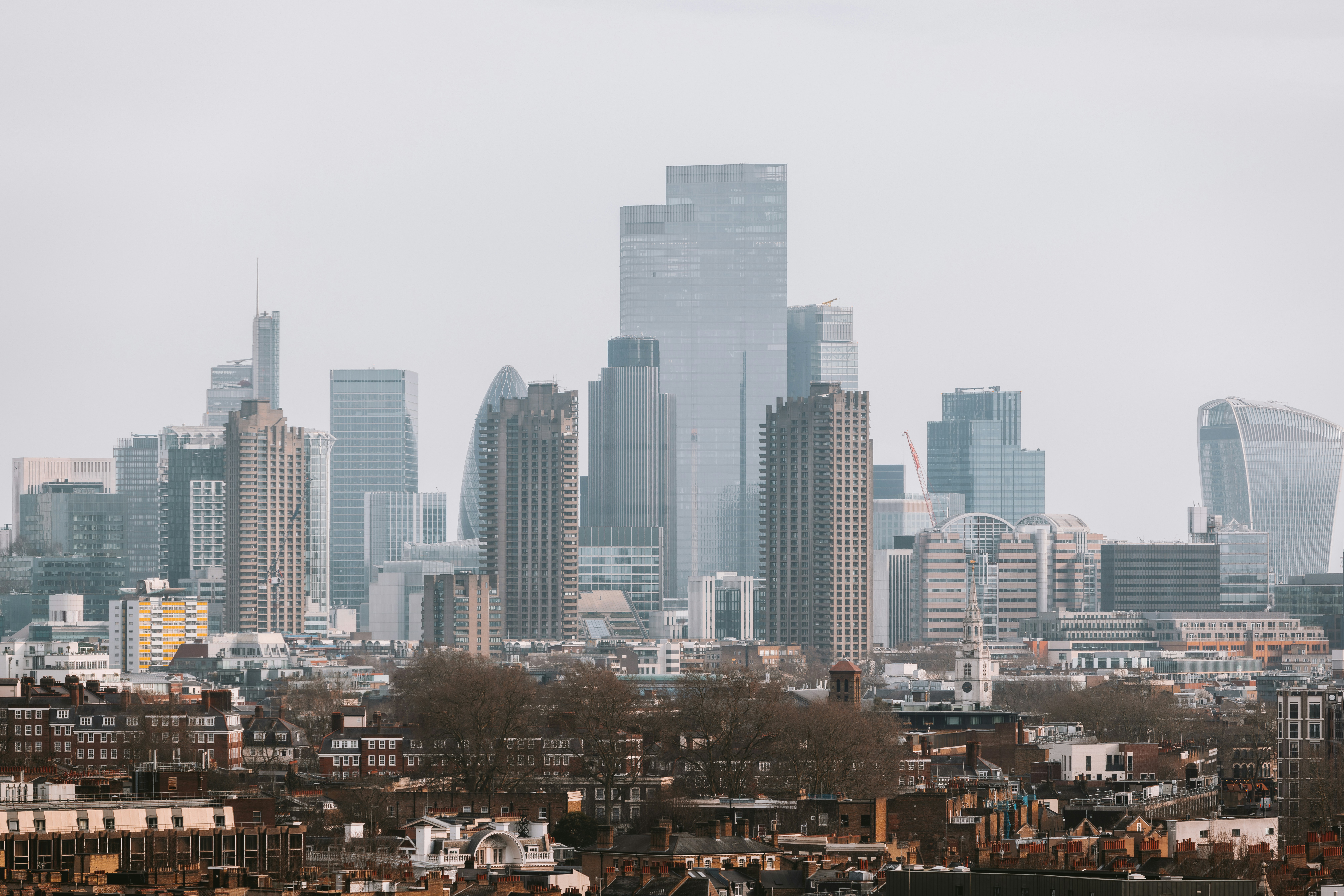 London skyline featuring modern skyscrapers contrasted with traditional buildings under a cloudy sky.