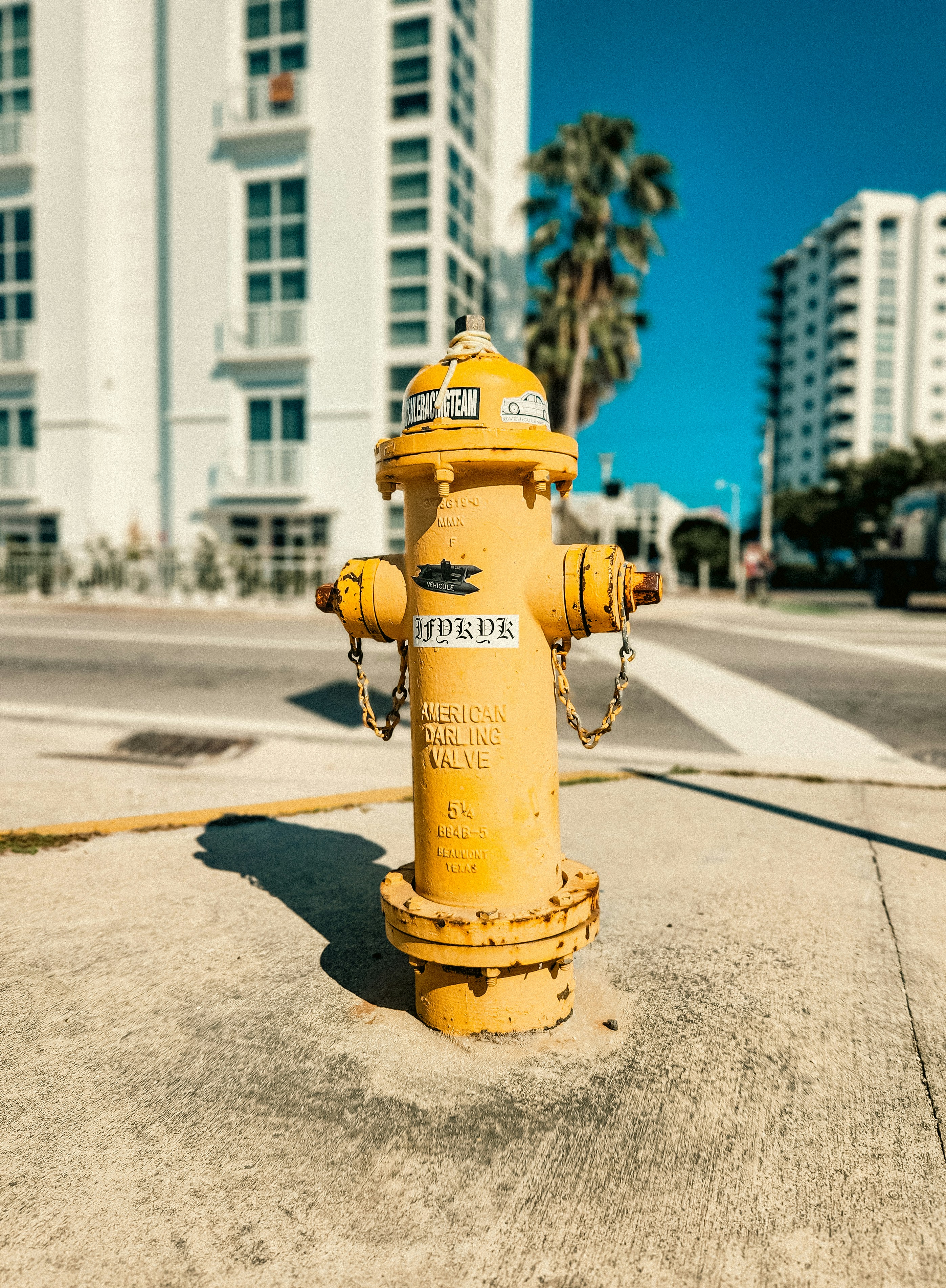 A yellow fire hydrant stands on the sidewalk, a vital part of the city's emergency water supply system. Painted yellow to indicate a public water source, it provides firefighters quick access in case of a fire. Typically made of cast iron, hydrants are connected to underground pipes and can deliver thousands of gallons per minute. Found on streets worldwide, their colors and markings often indicate water pressure levels. Regularly maintained by municipal authorities, they are essential for urban fire safety and preparedness.