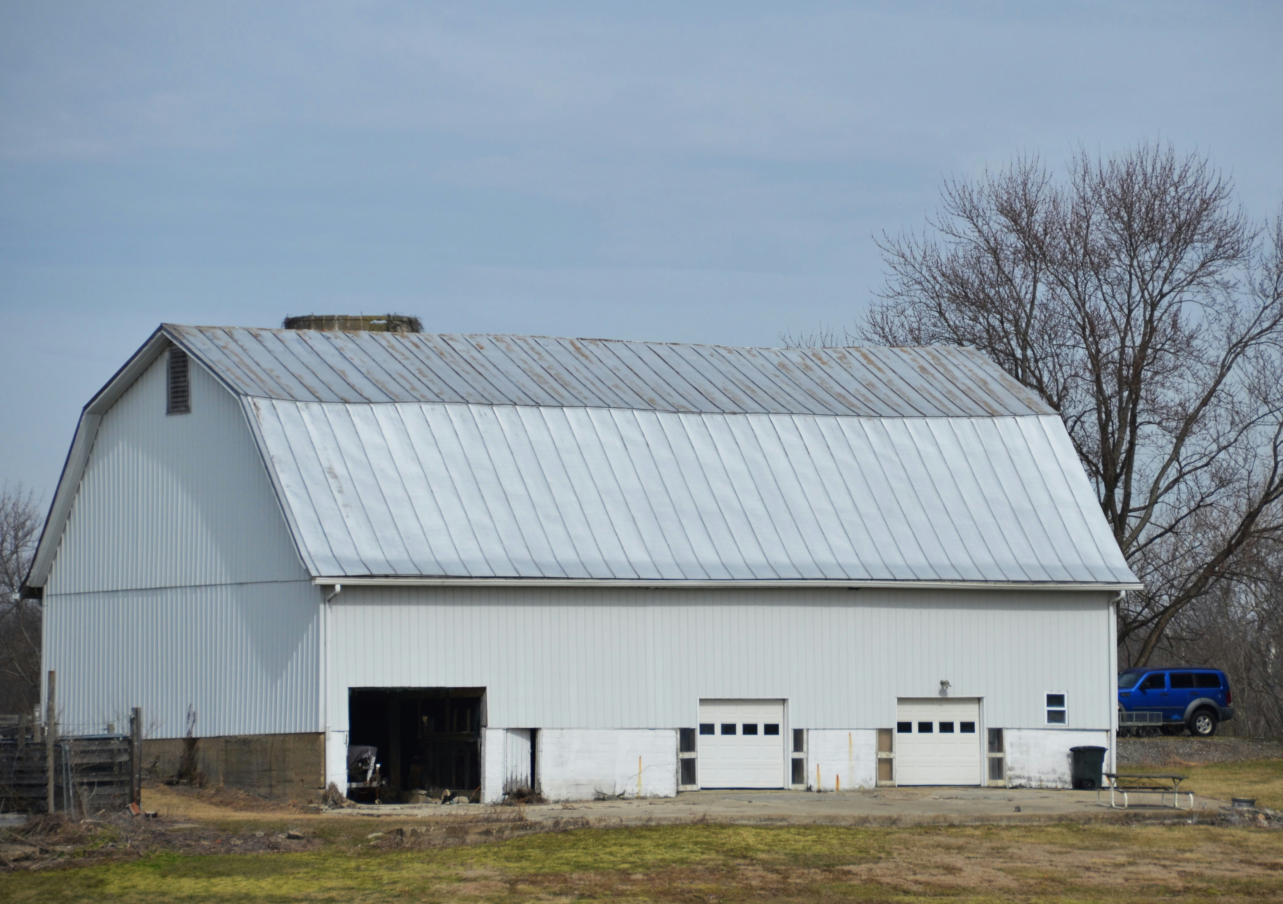 A large white barn with a blue truck in the background photo – Free ...