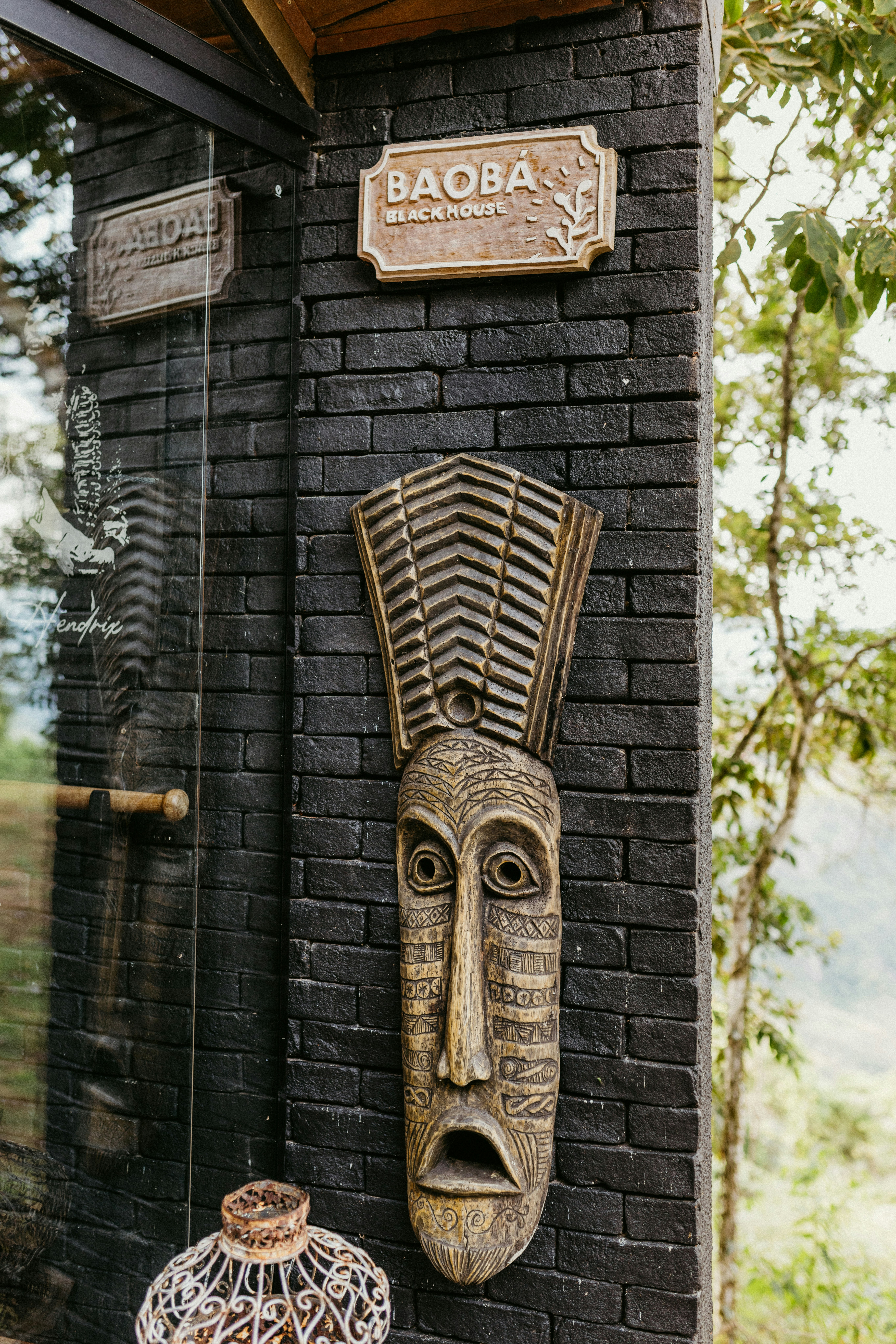 Baoba's Guardian: Carved Mask Anchored to a Brick Wall