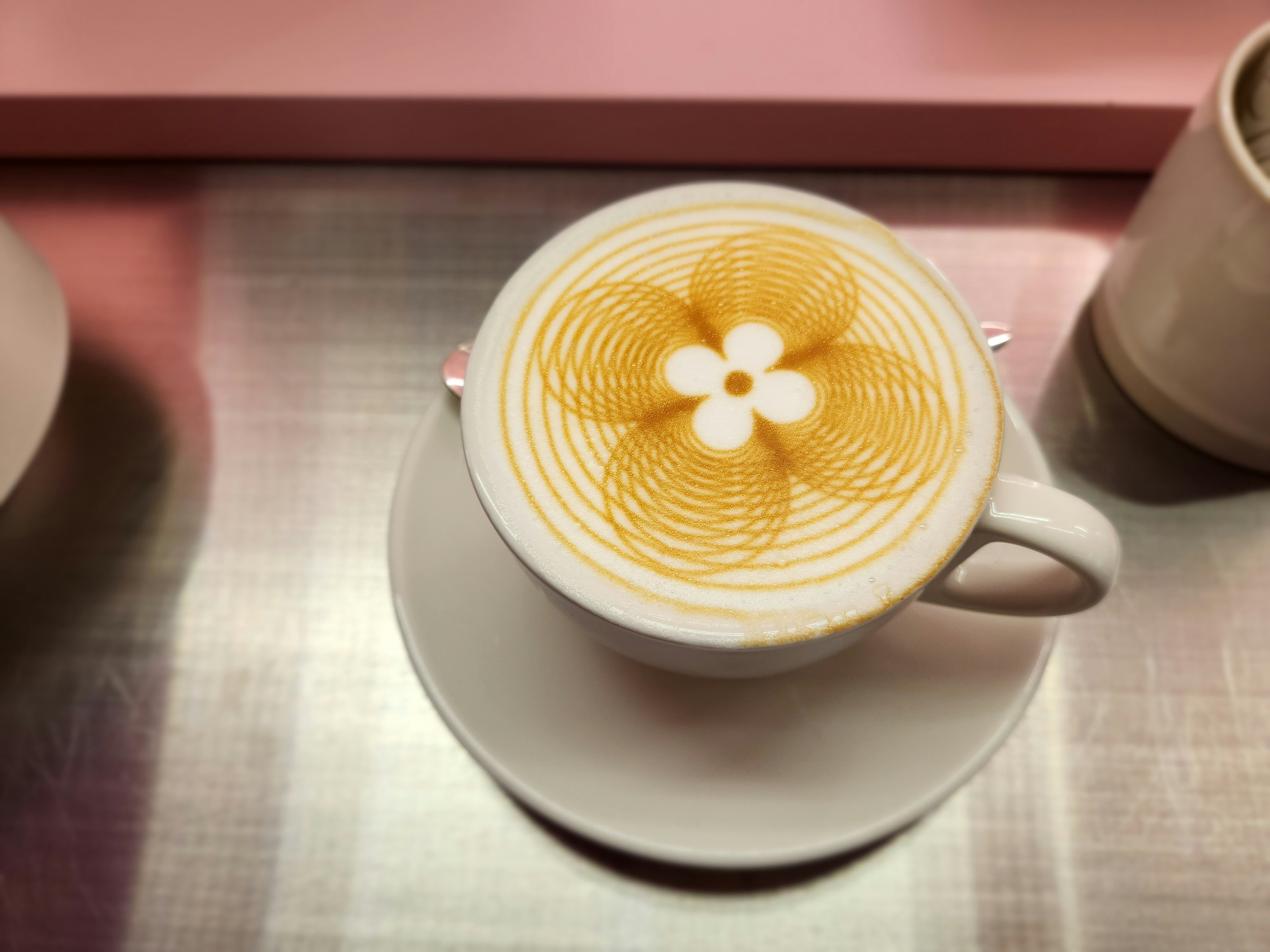 Caramel Flower Latte: Delicate Swirls on a Pink Café Counter
