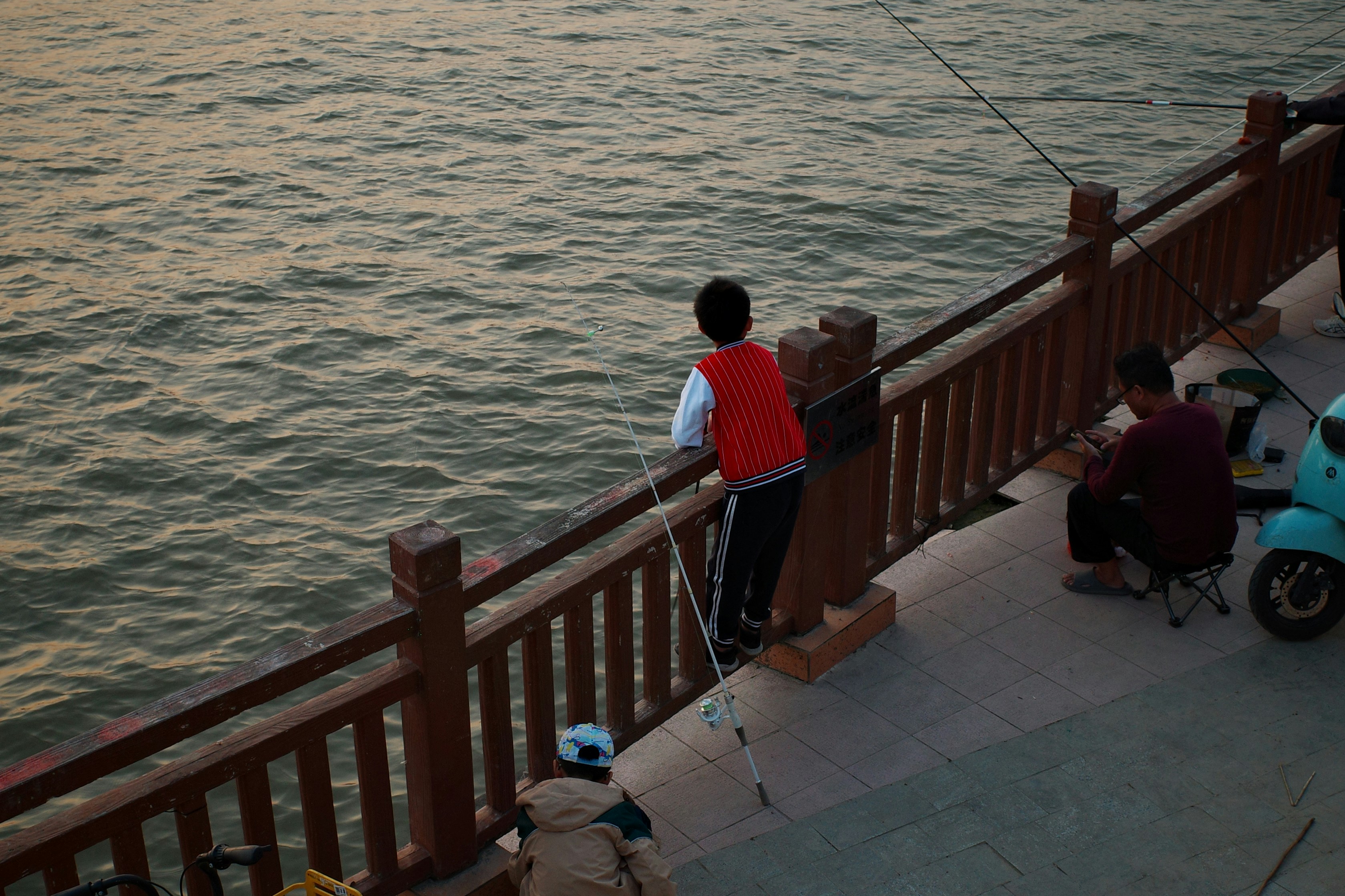 Red-Vest Angler at the Railing: A Tranquil Riverside Moment
