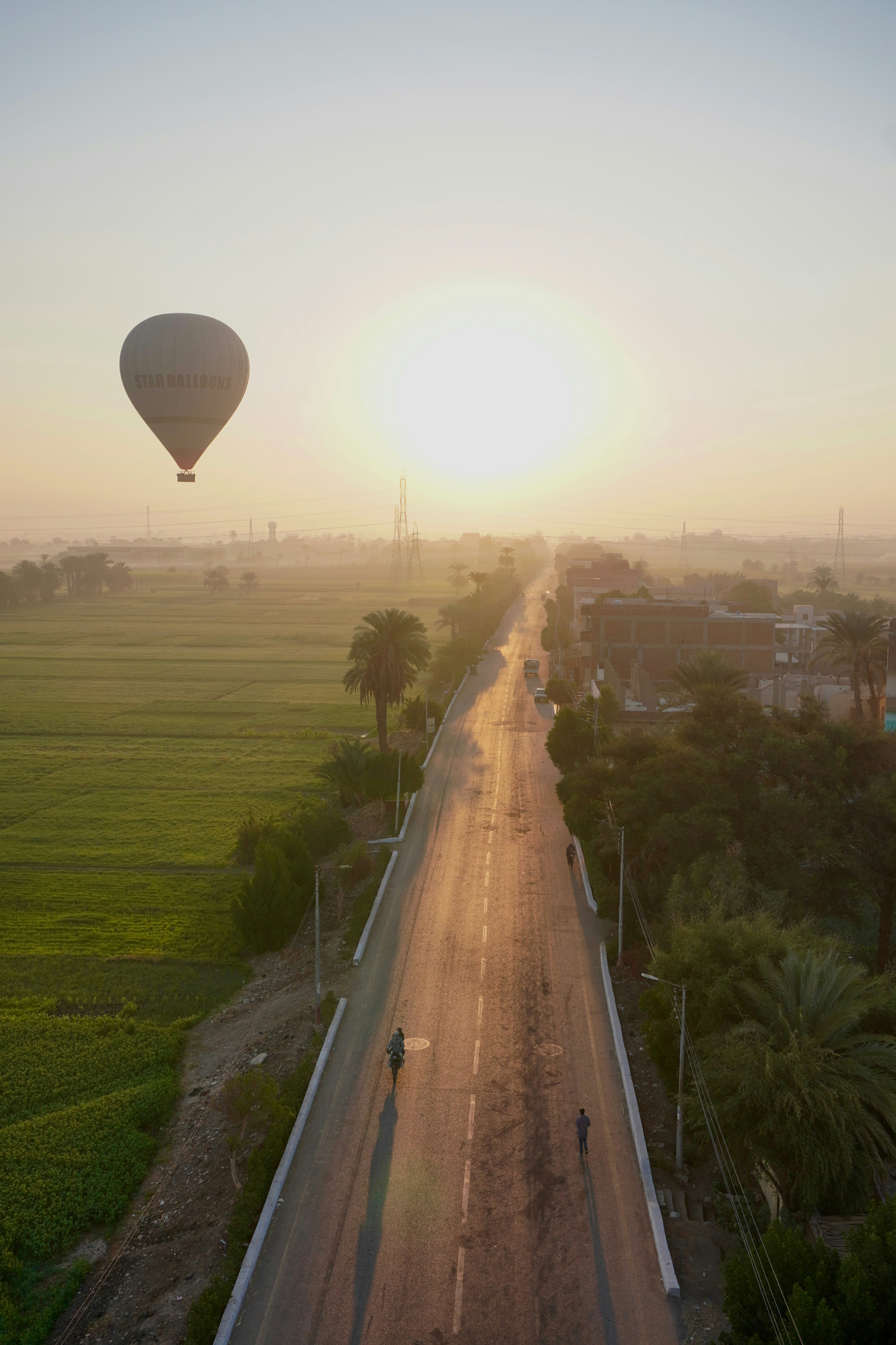 Sunrise over the rural highway: a lone balloon drifts above the fields