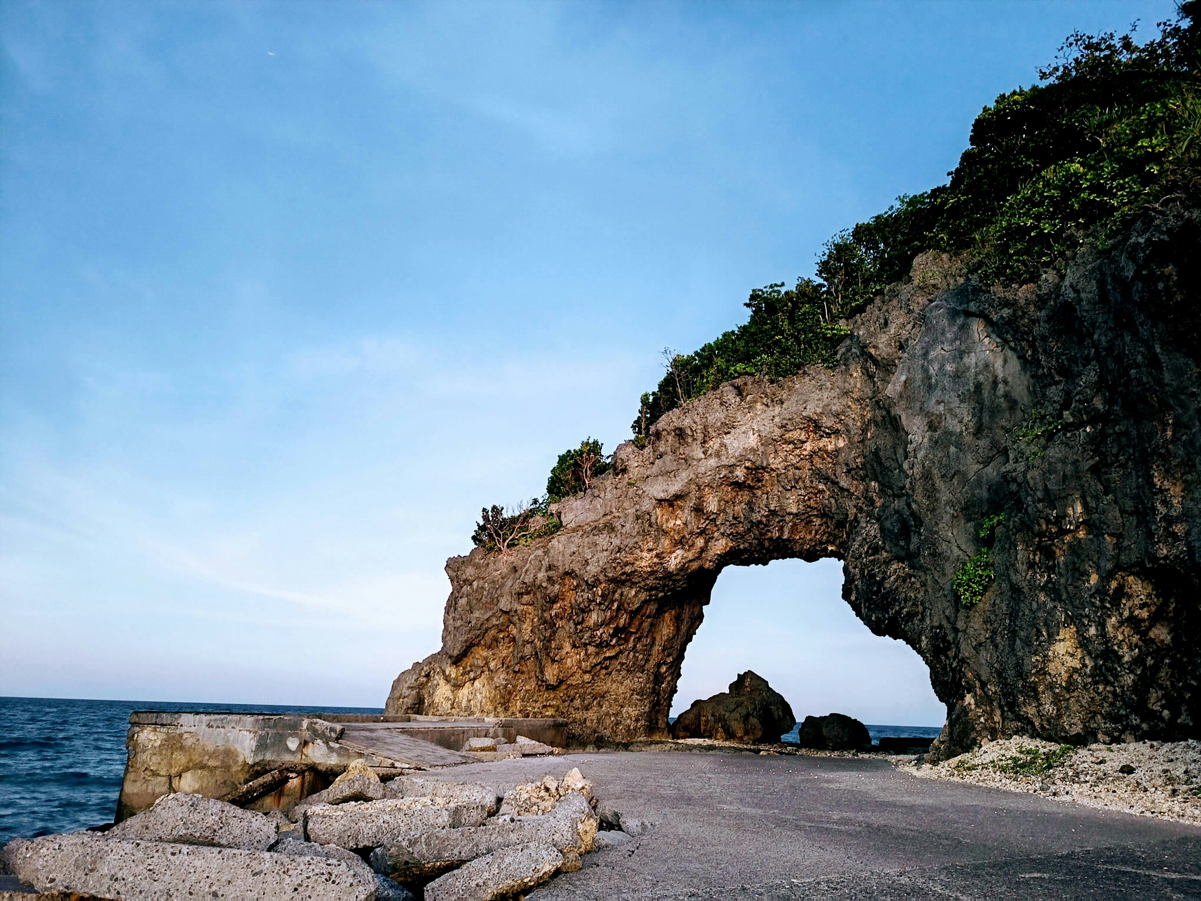 Rock arch formation by the sea under a clear blue sky.