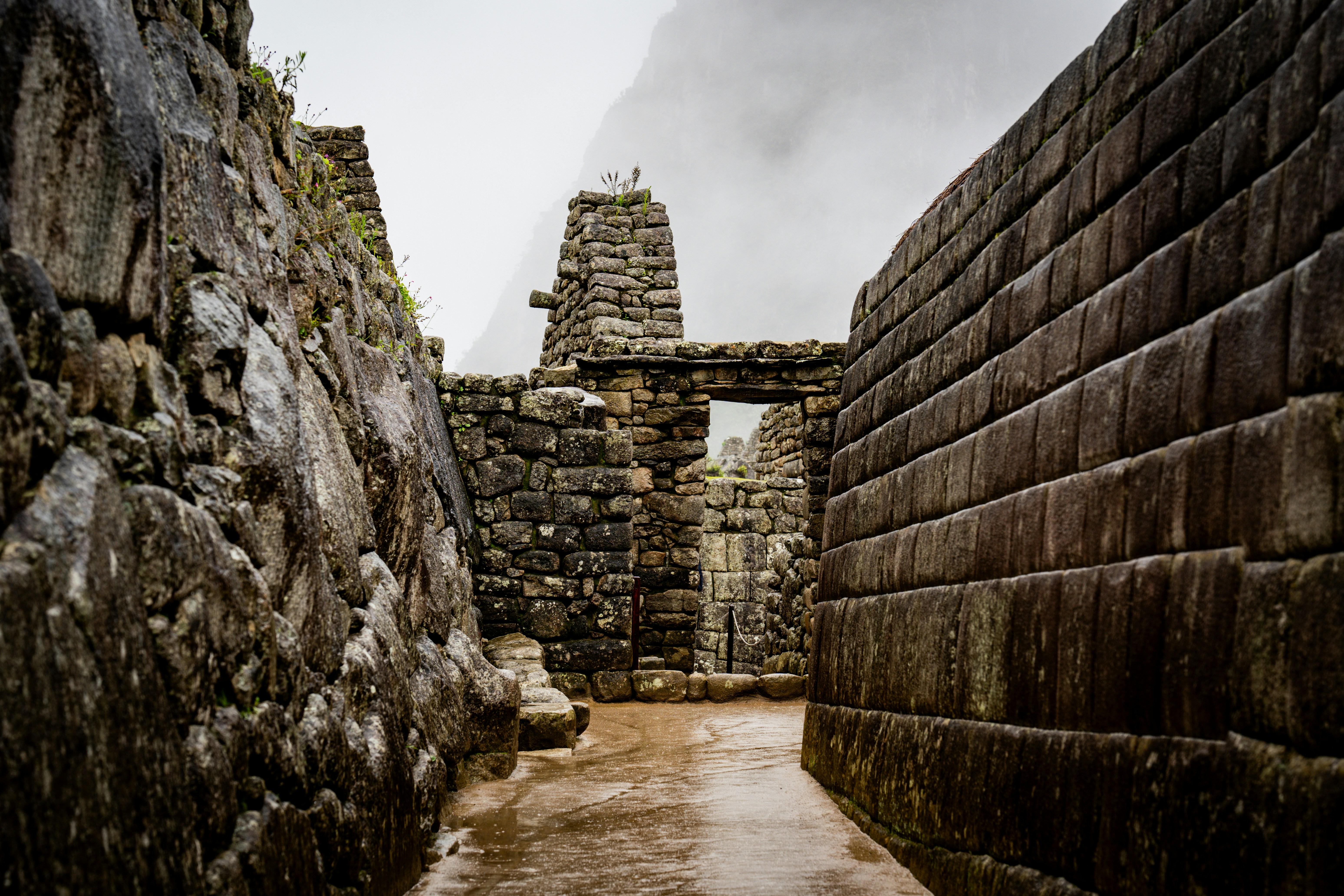 Stone pathway leading to an ancient stone archway amidst misty mountains.
