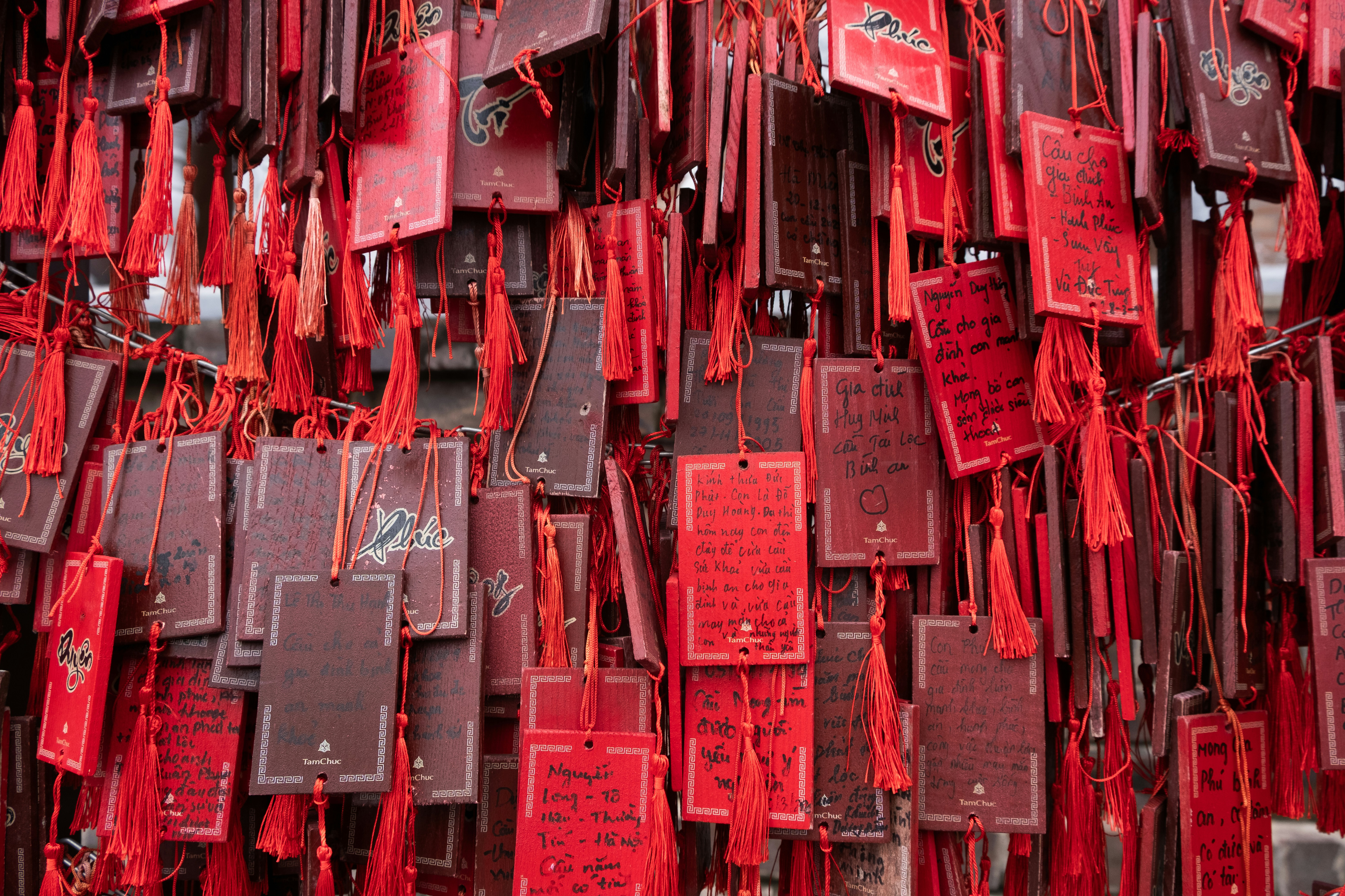Red and brown wish plaques with tassels densely hung together.