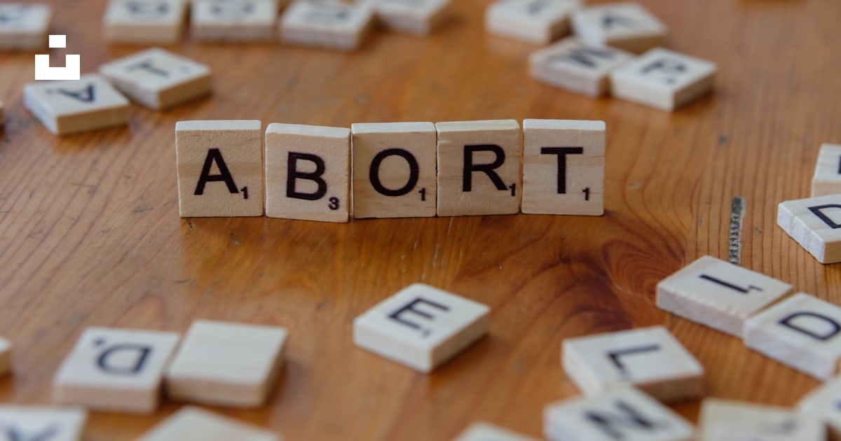 스크래블 타일이 깔린 나무 테이블에는 Abort라는 단어가 적혀 있습니다 사진 Unsplash의 무료 수 이미지