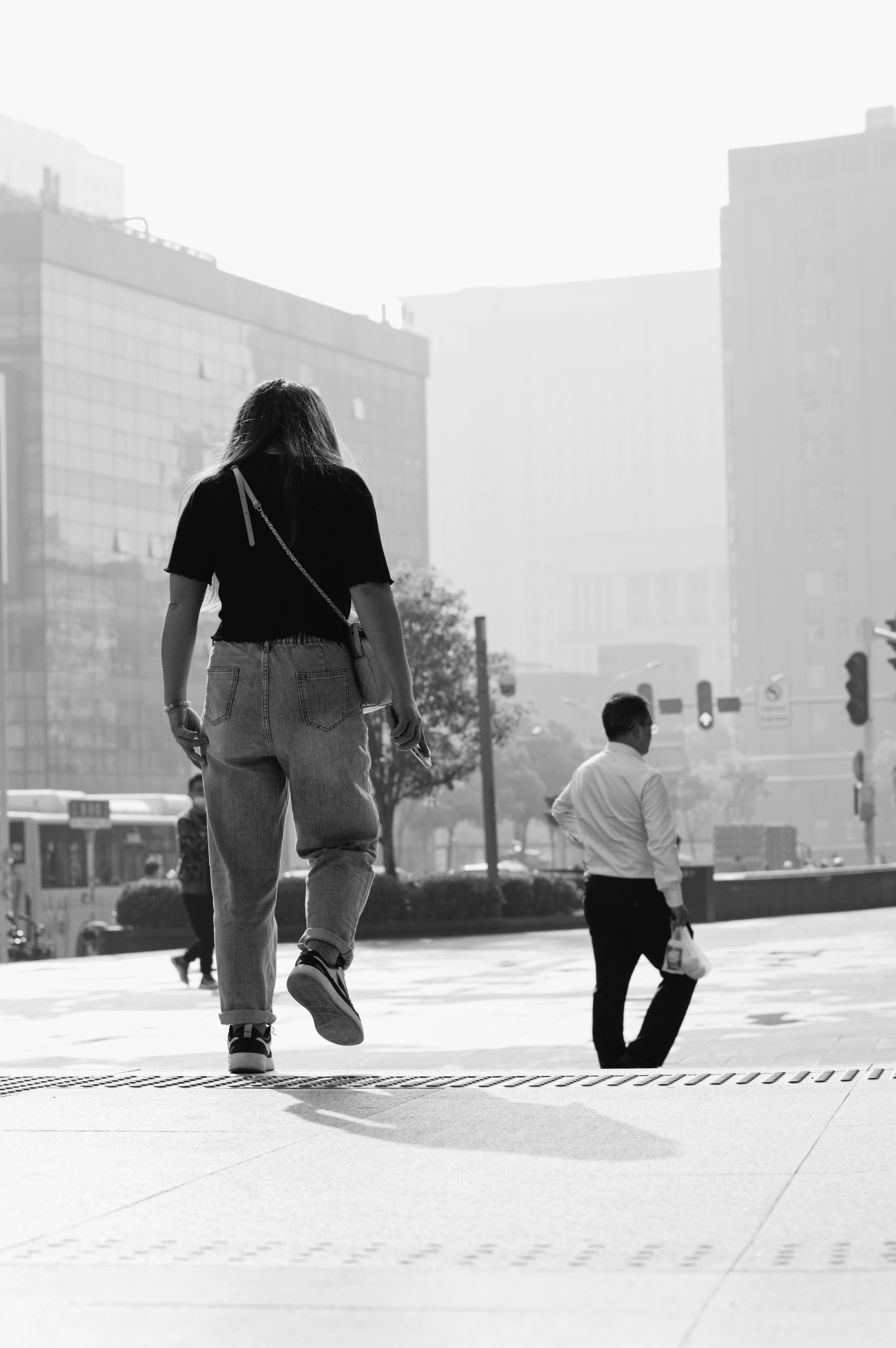 Back-View Momentum: A Lone Figure Crossing a Quiet Greyscale City Square